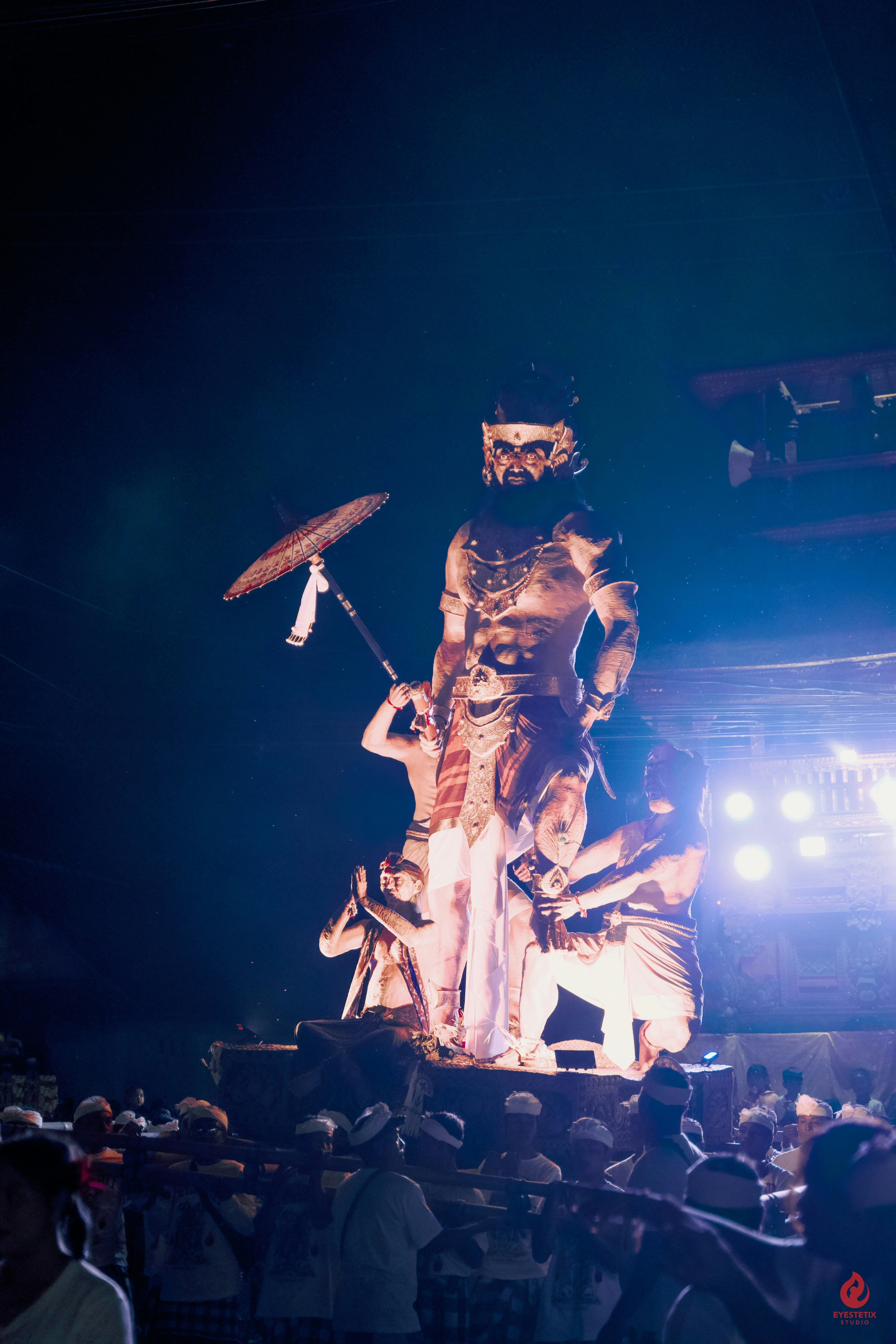 Statue of the Mythic Guardian Surrounded by Worshippers Under Stage Lights