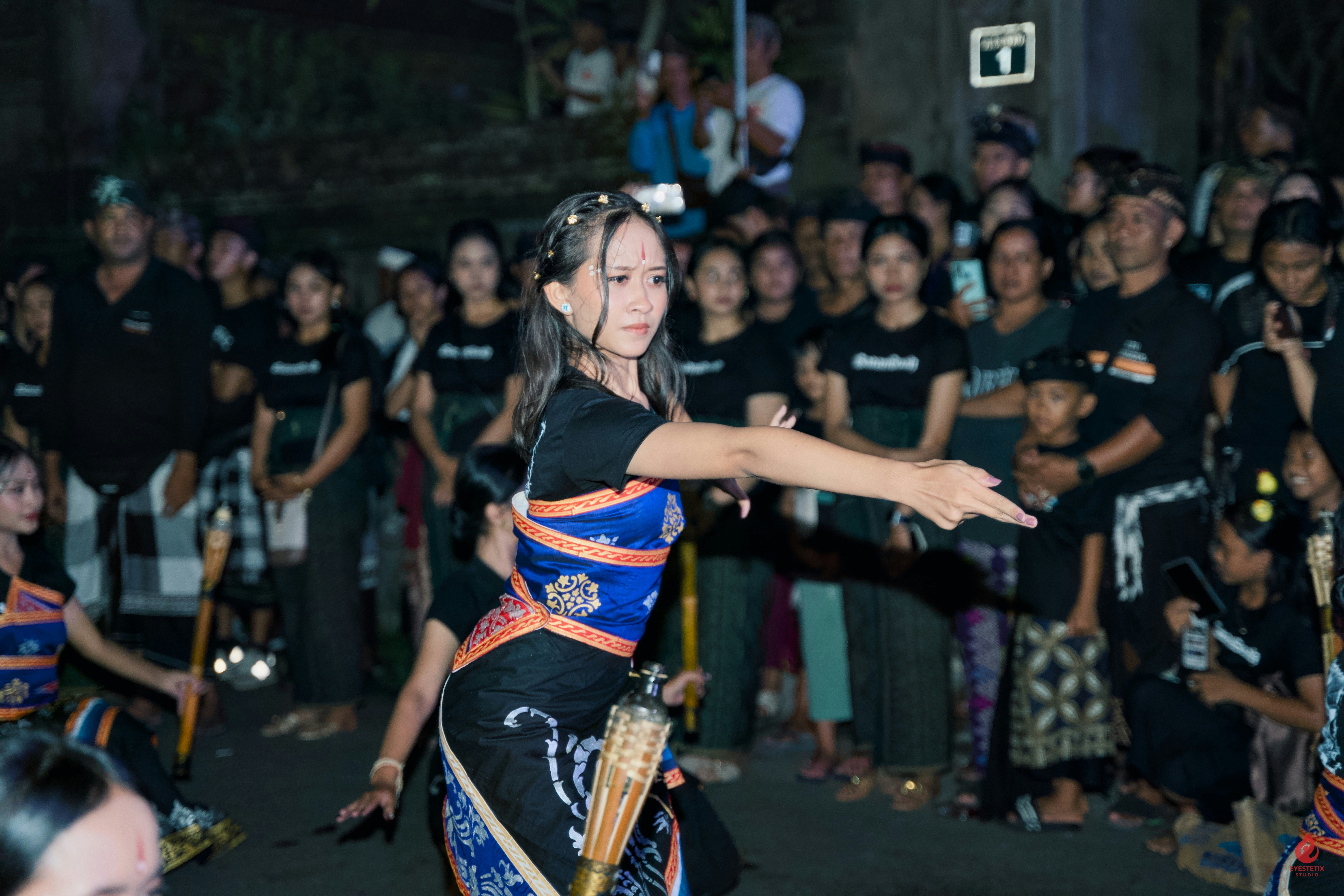 Dance of the Flame: A Central Performer Among a Nighttime Crowd