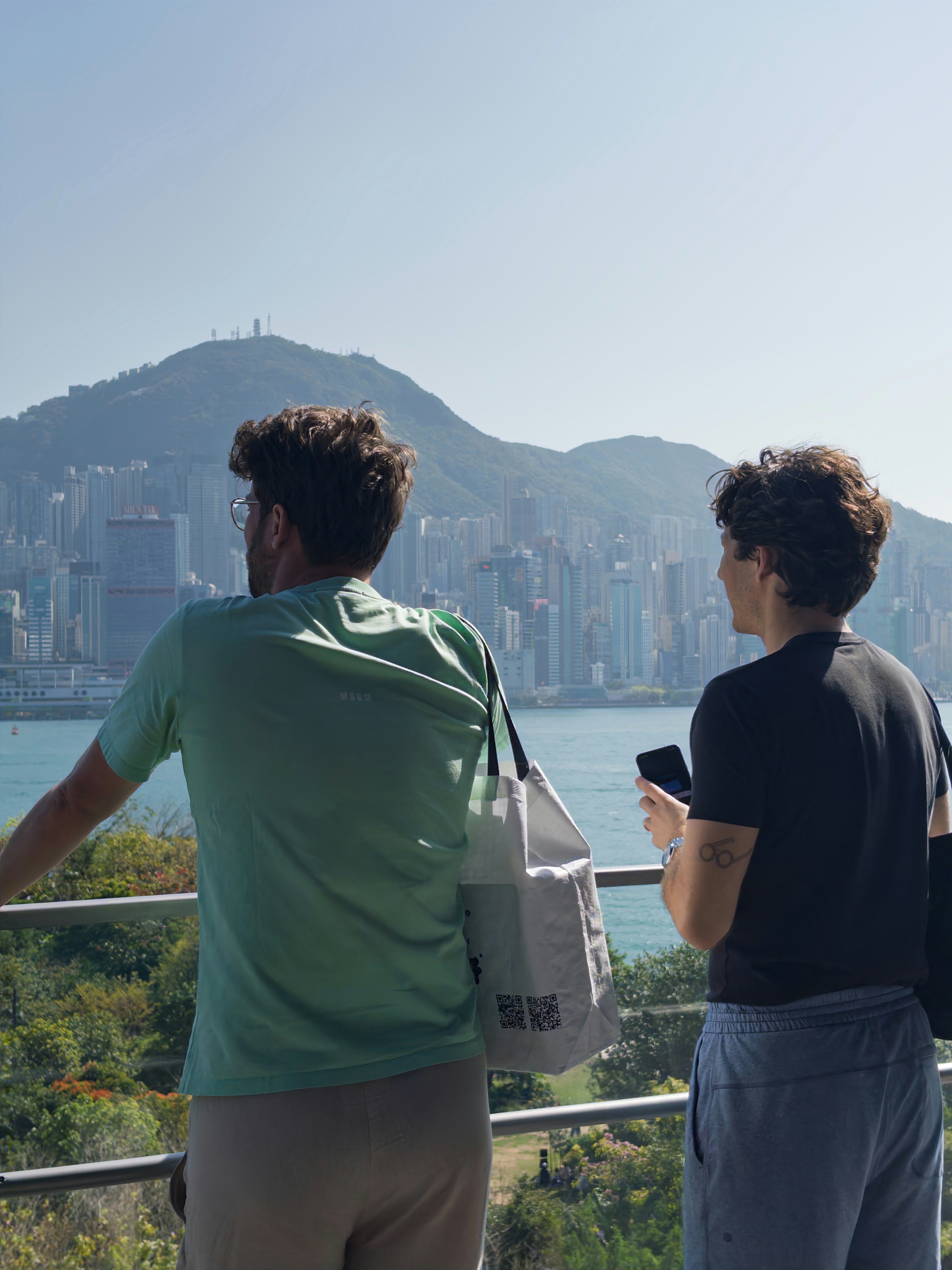 Two people look out at a city skyline and ocean.