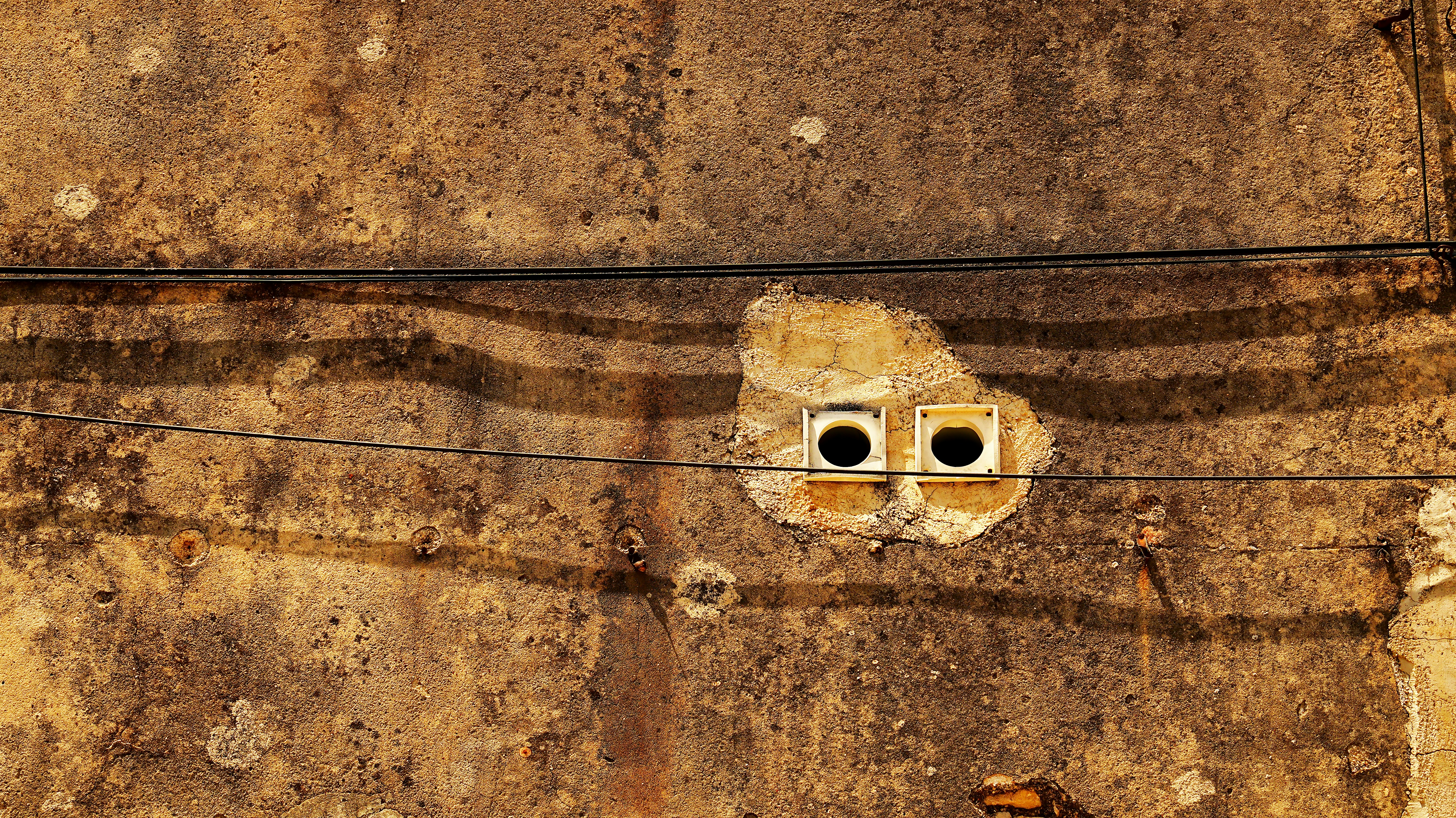 Two Square Holes in a Weathered Concrete Wall