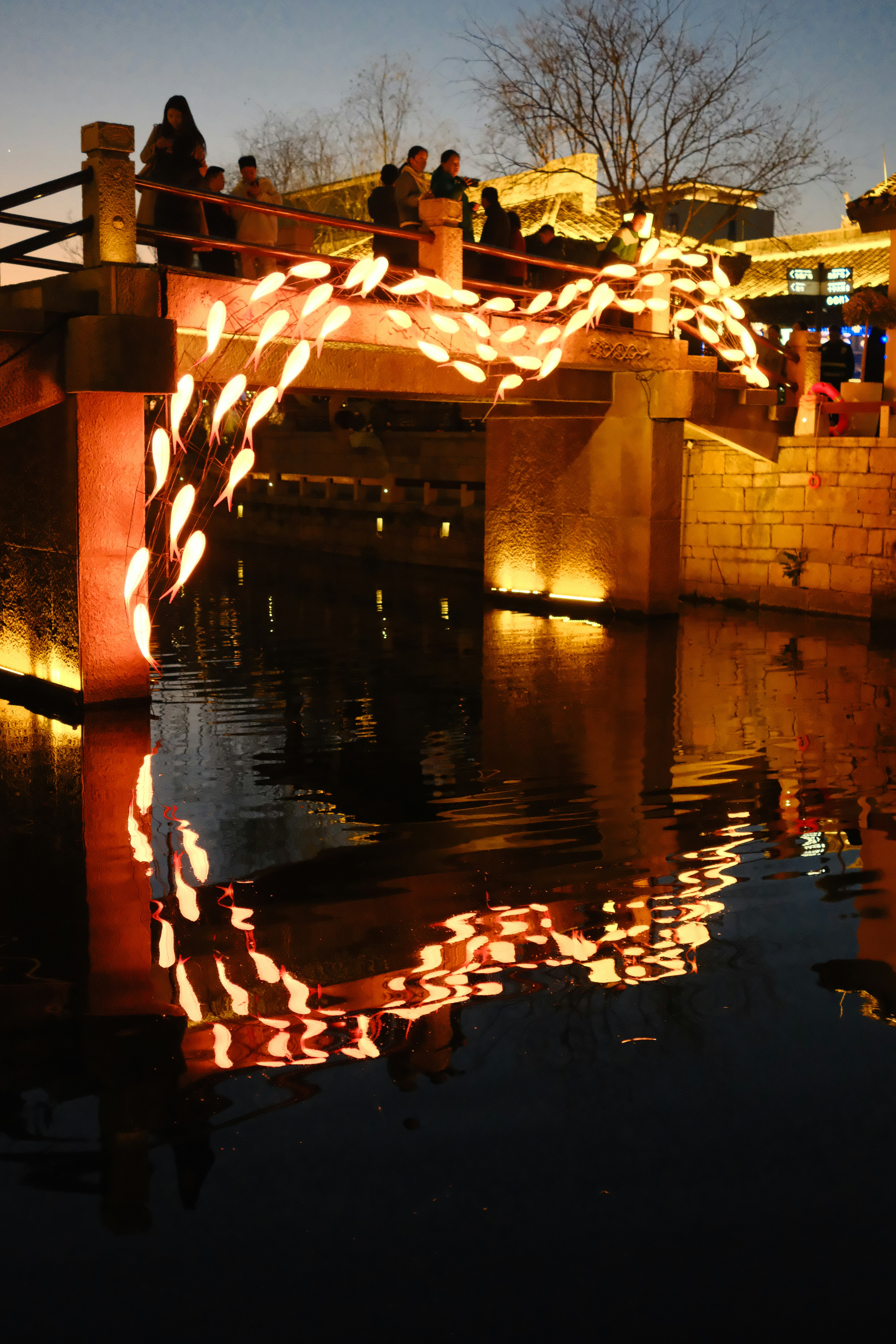 Fire-lit arc across the canal: reflections and silhouettes under evening glow
