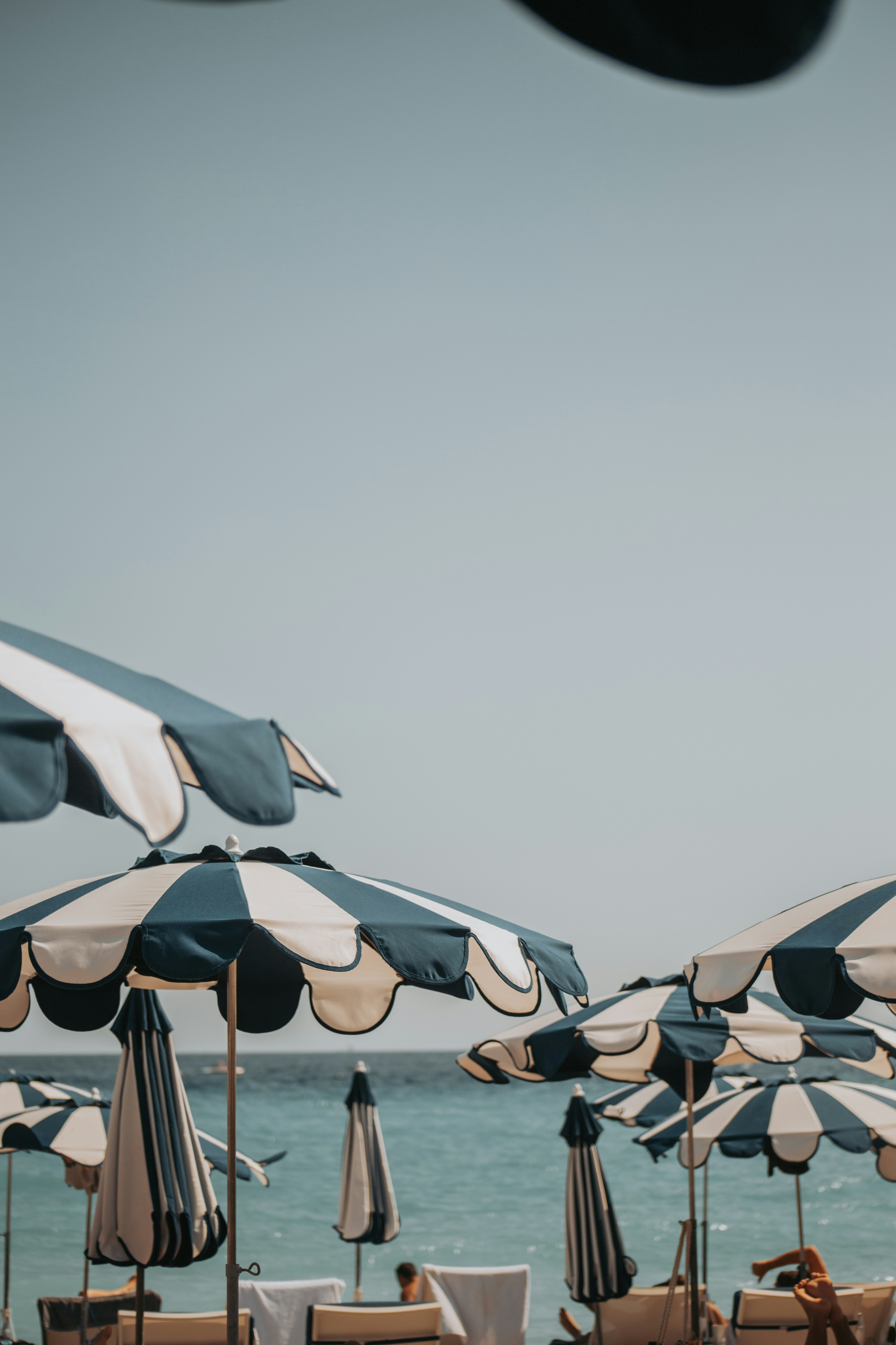 Shade and Sea: A Quiet Beach Scene Beneath Striped Canopies