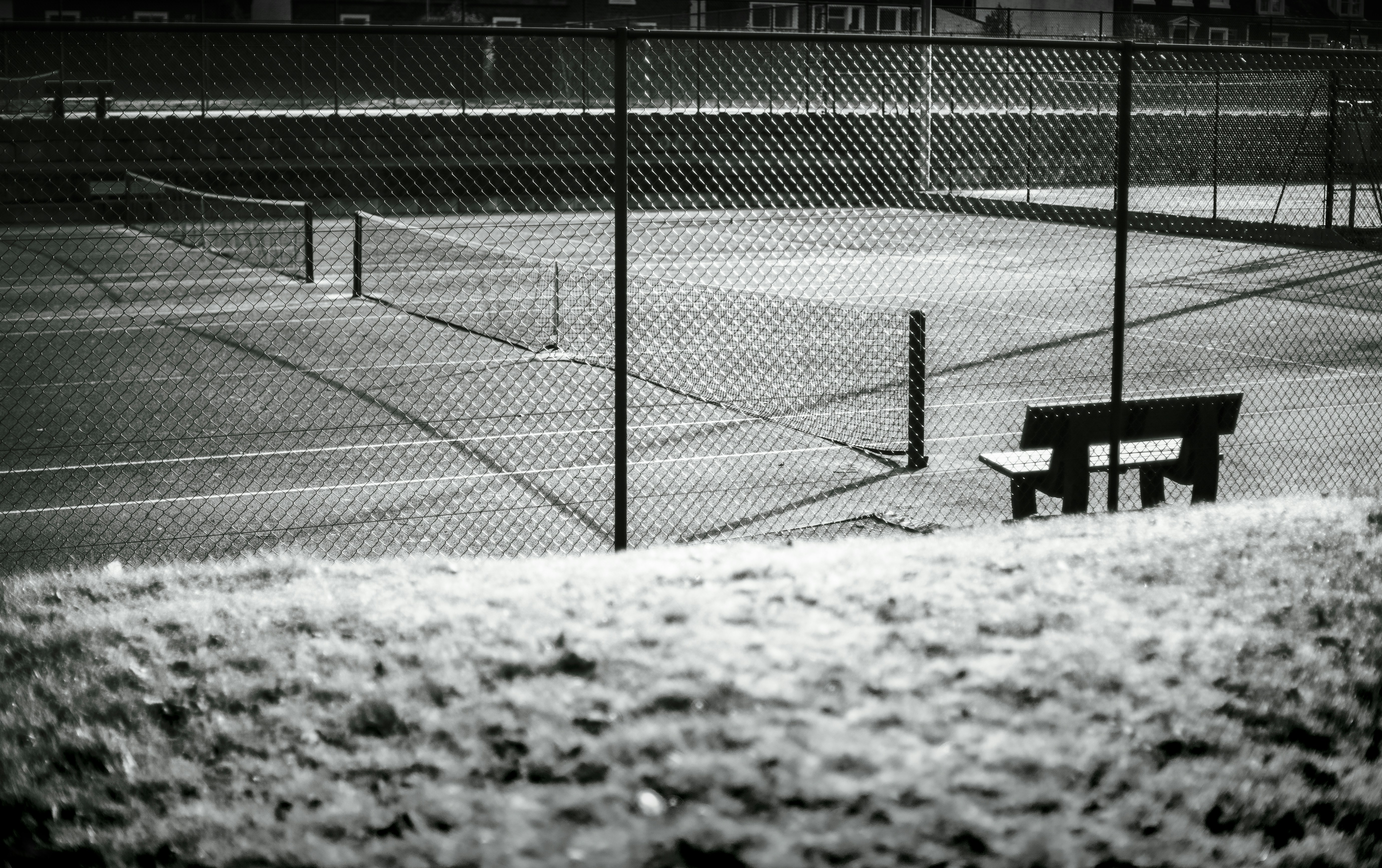 Empty Park Bench Beside a Quiet Tennis Court