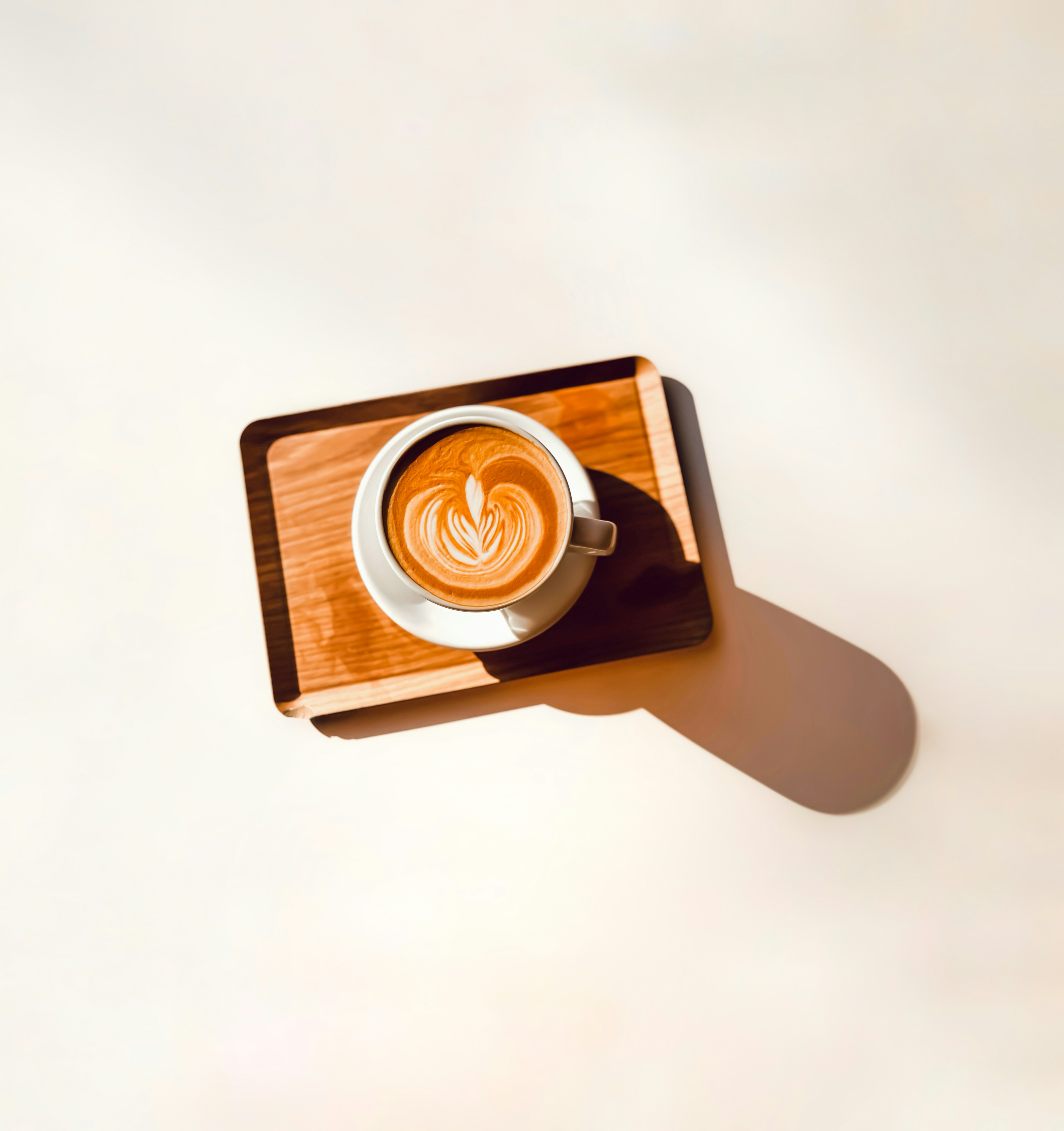 Overhead Café Glow: Latte Art on a Wooden Tray