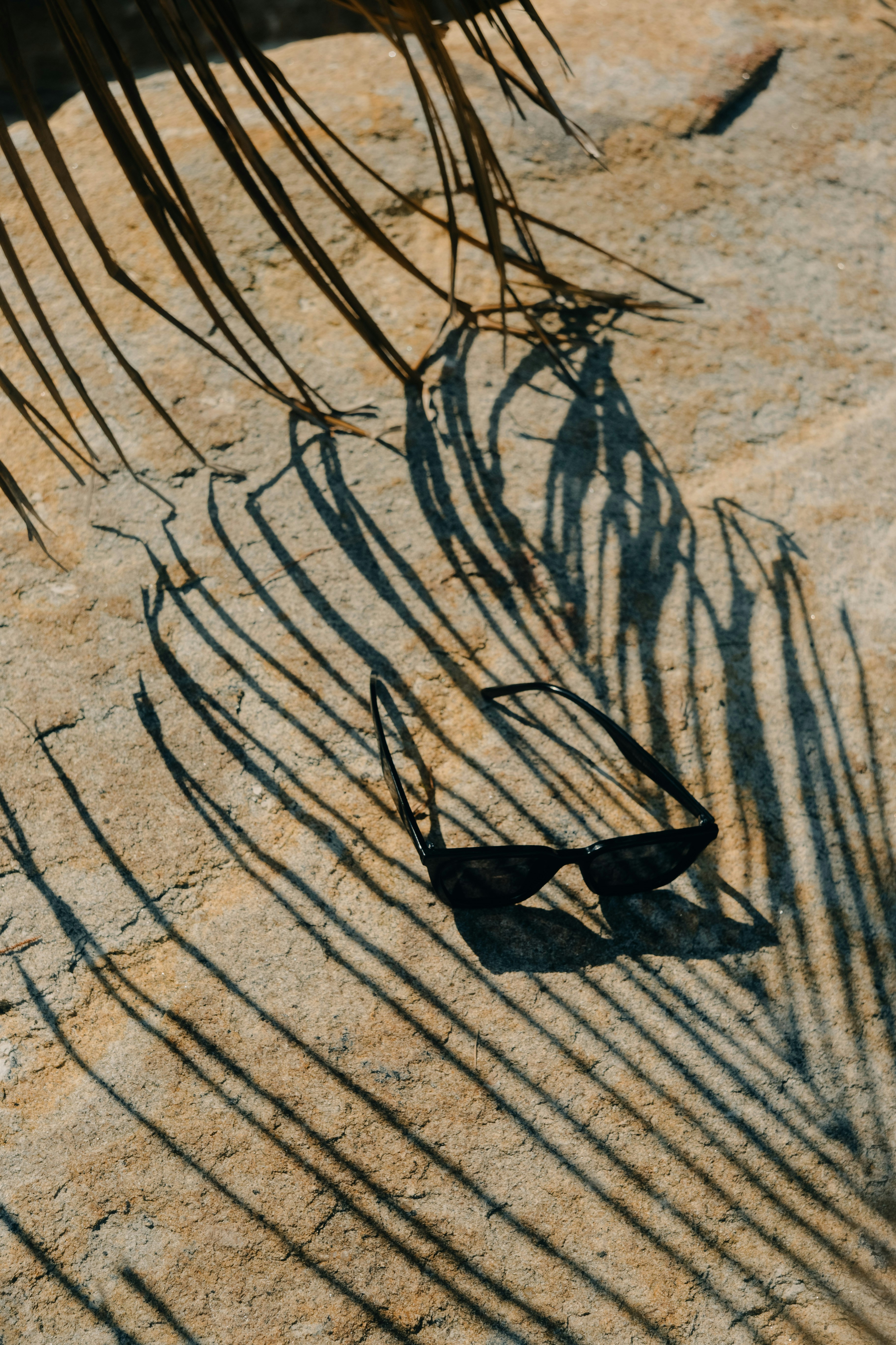 Shadowed Sunglasses on Sunlit Sand