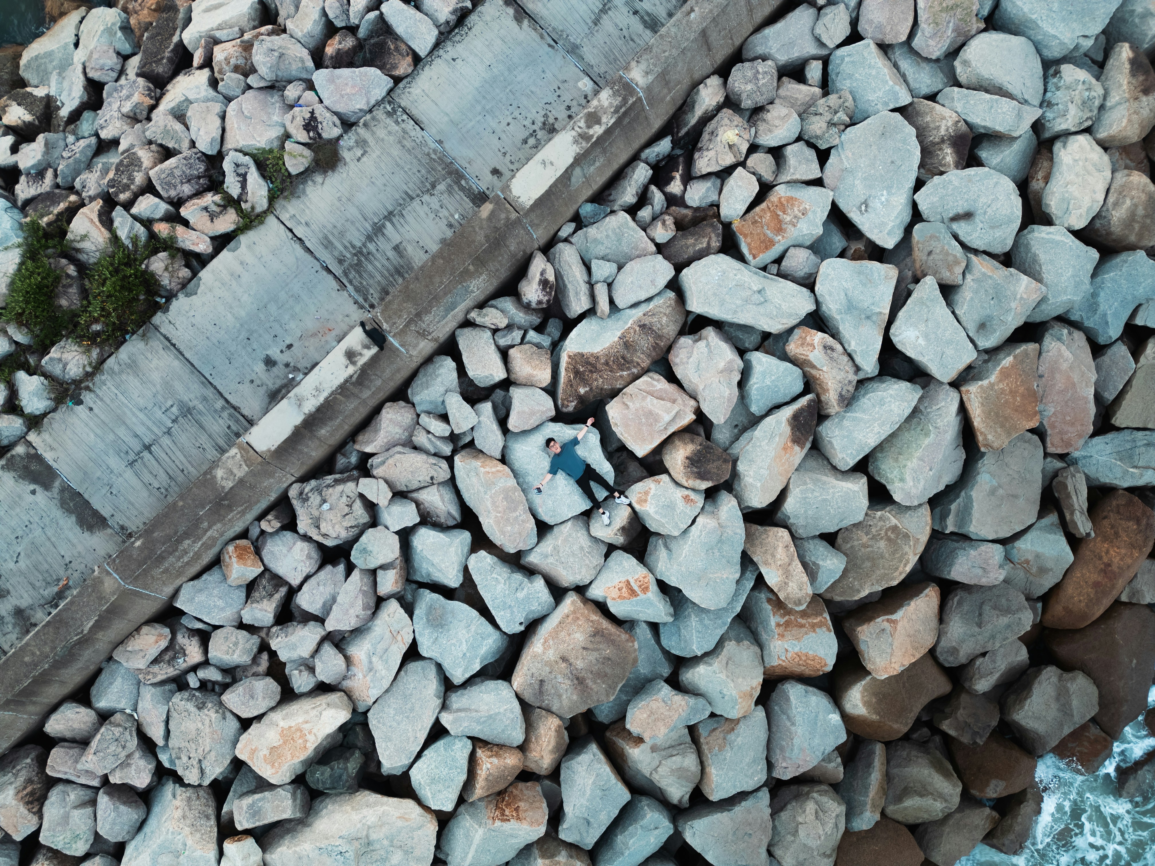 Rugged shoreline of angular stones with a lone figure amid the gravel