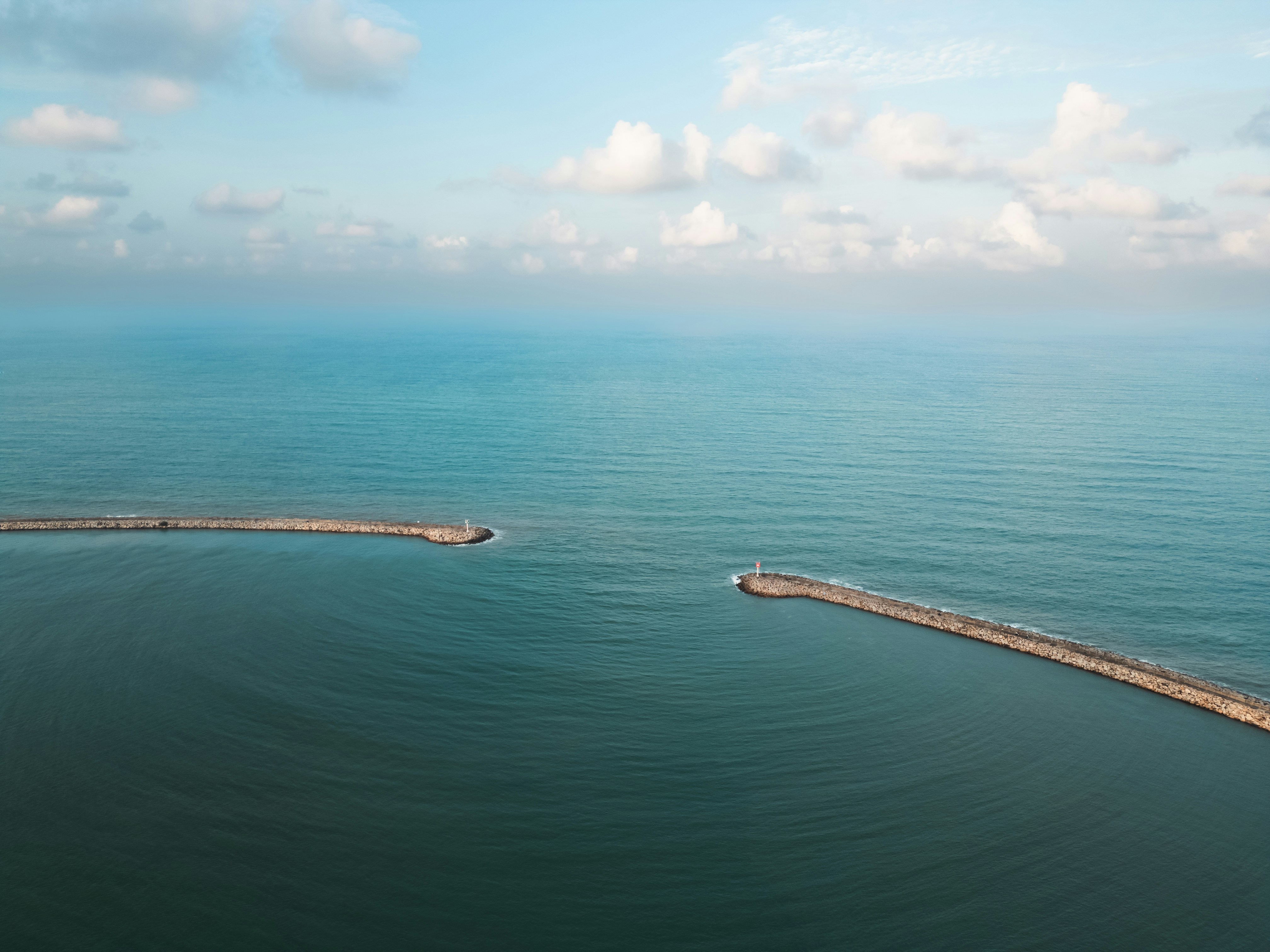 Converging Breakwaters Embrace a Calm Ocean Sky