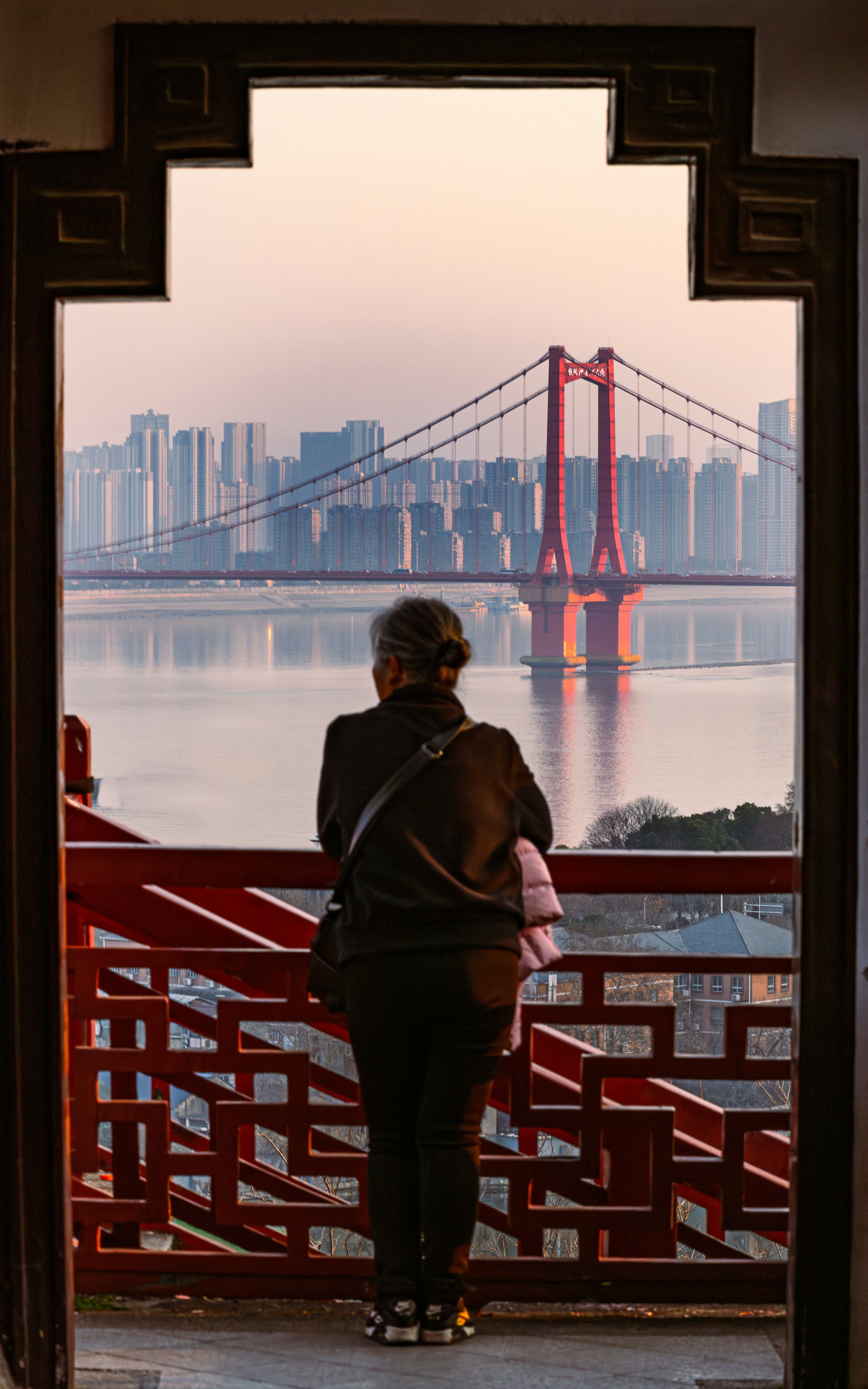 Silhouette at Dusk: Viewer’s Gaze Toward the Red Suspension Bridge