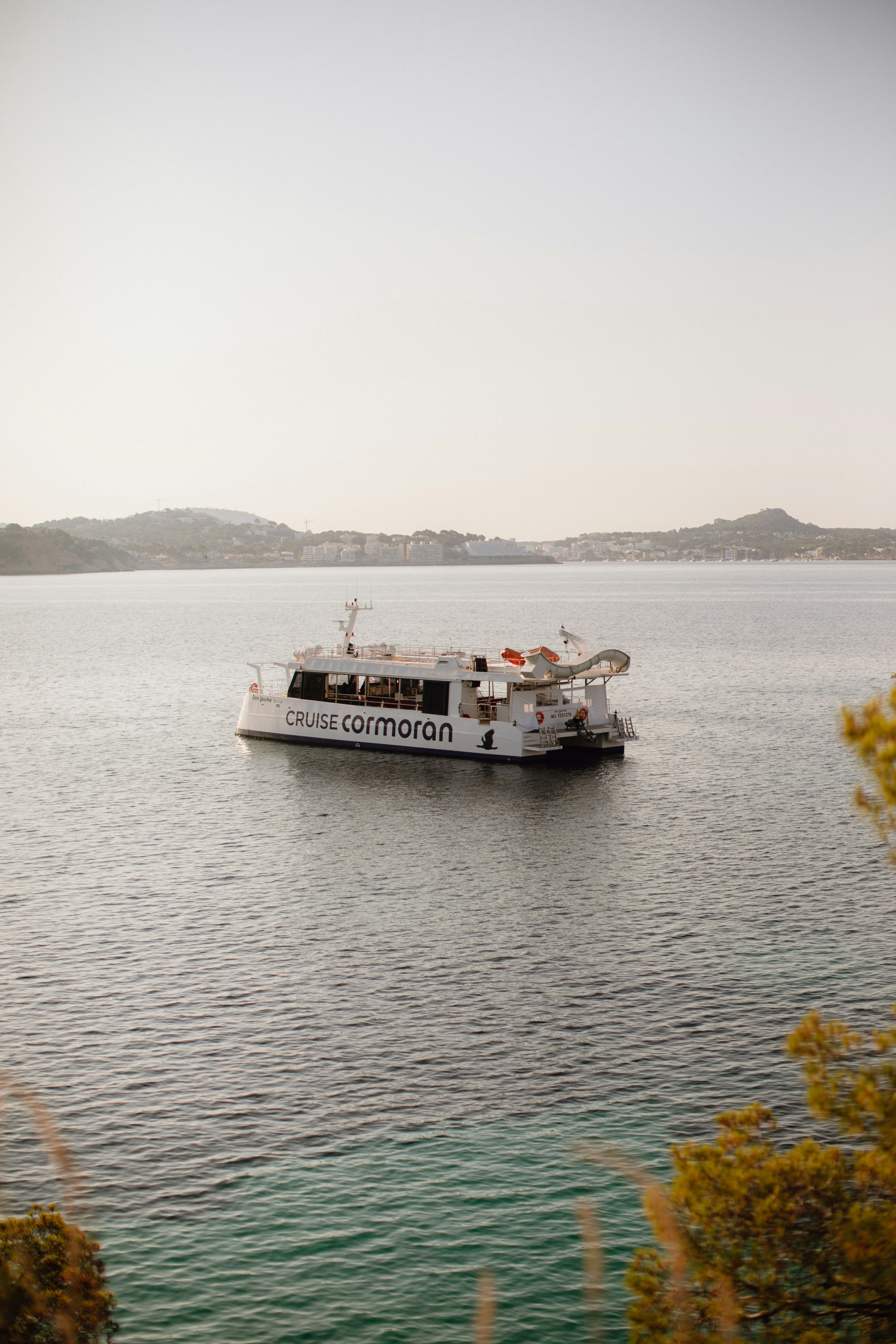 Boat named Cruise Cormoran gliding across a calm bay at golden hour