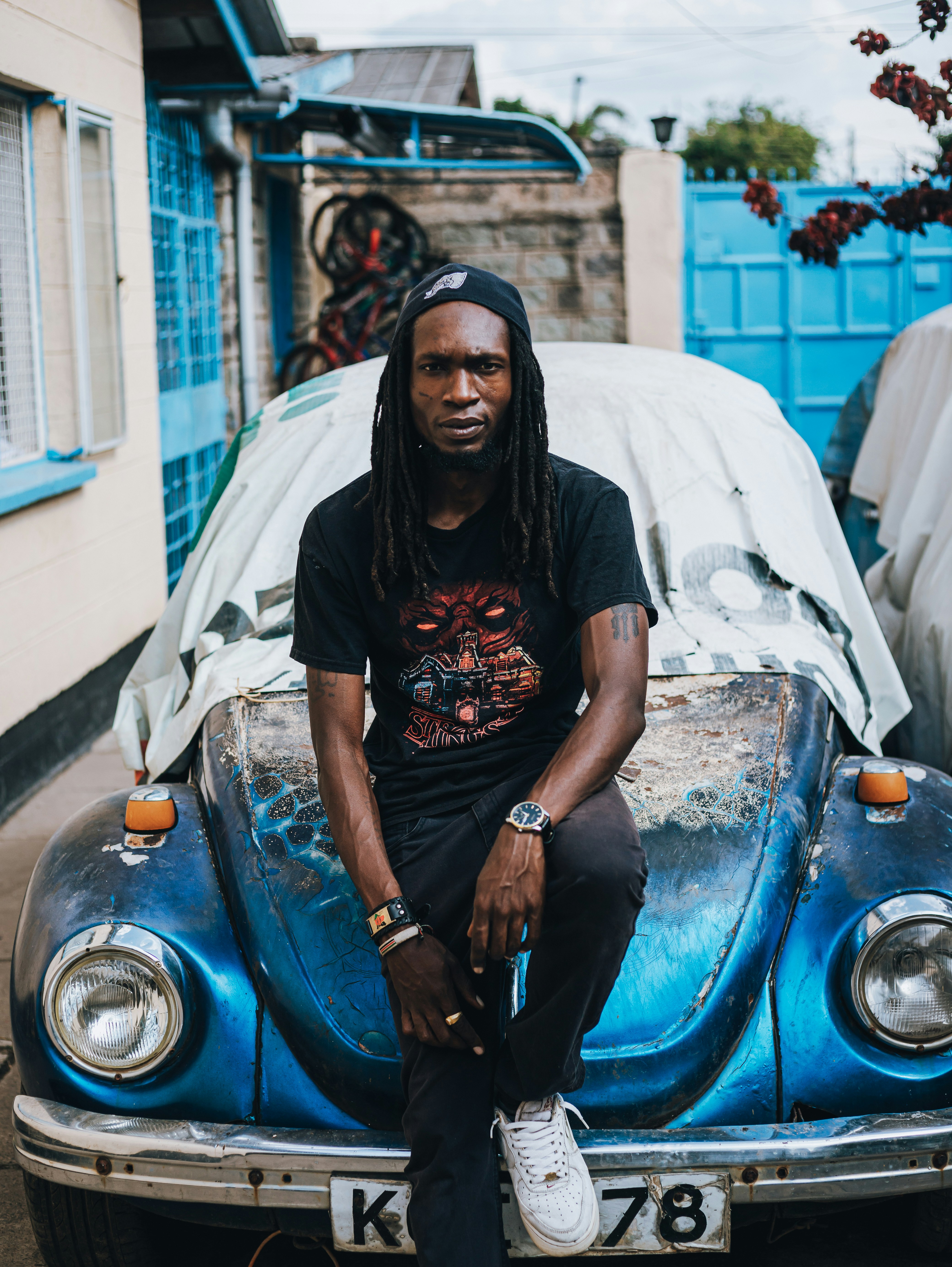 Portrait on chrome and blue: a rider sits center on a weathered VW Beetle