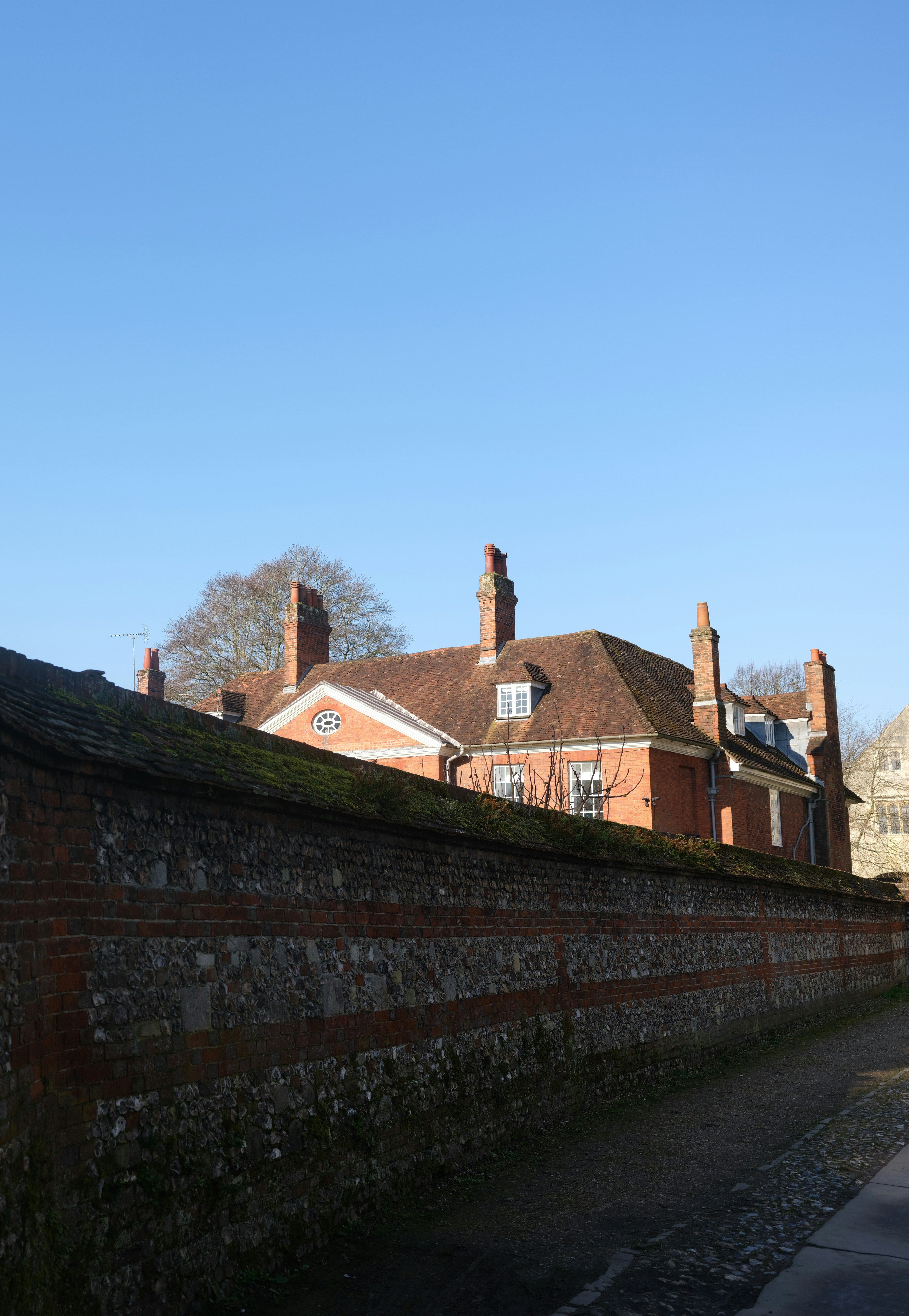 Red Brick Estate Behind a Mossy Brick Wall at Dusk