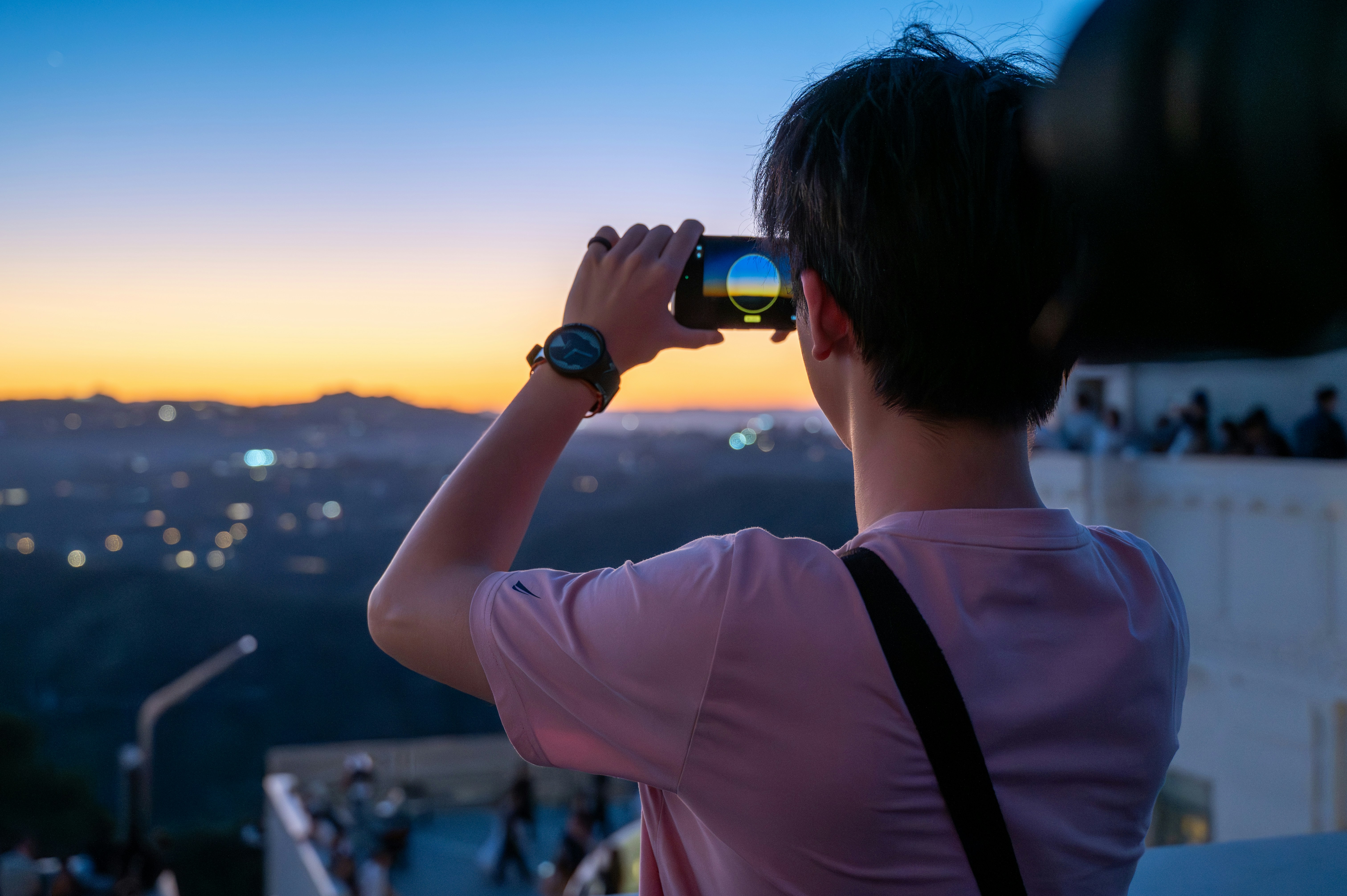 Cityscape Gaze: A Sunset Scene Framed by a Photographer in Pink