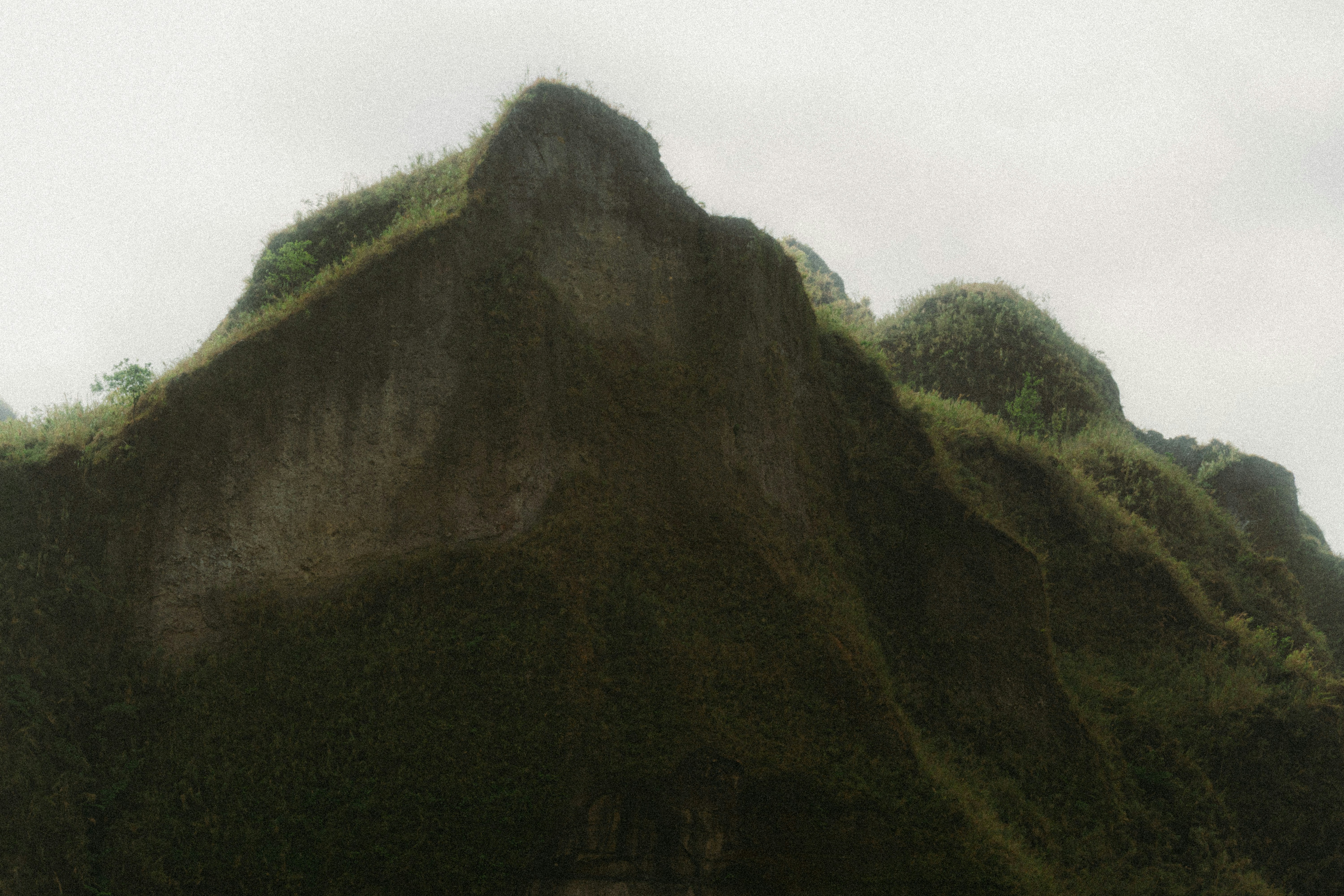 A Verdant Peak Looms Over a Weathered Cliff