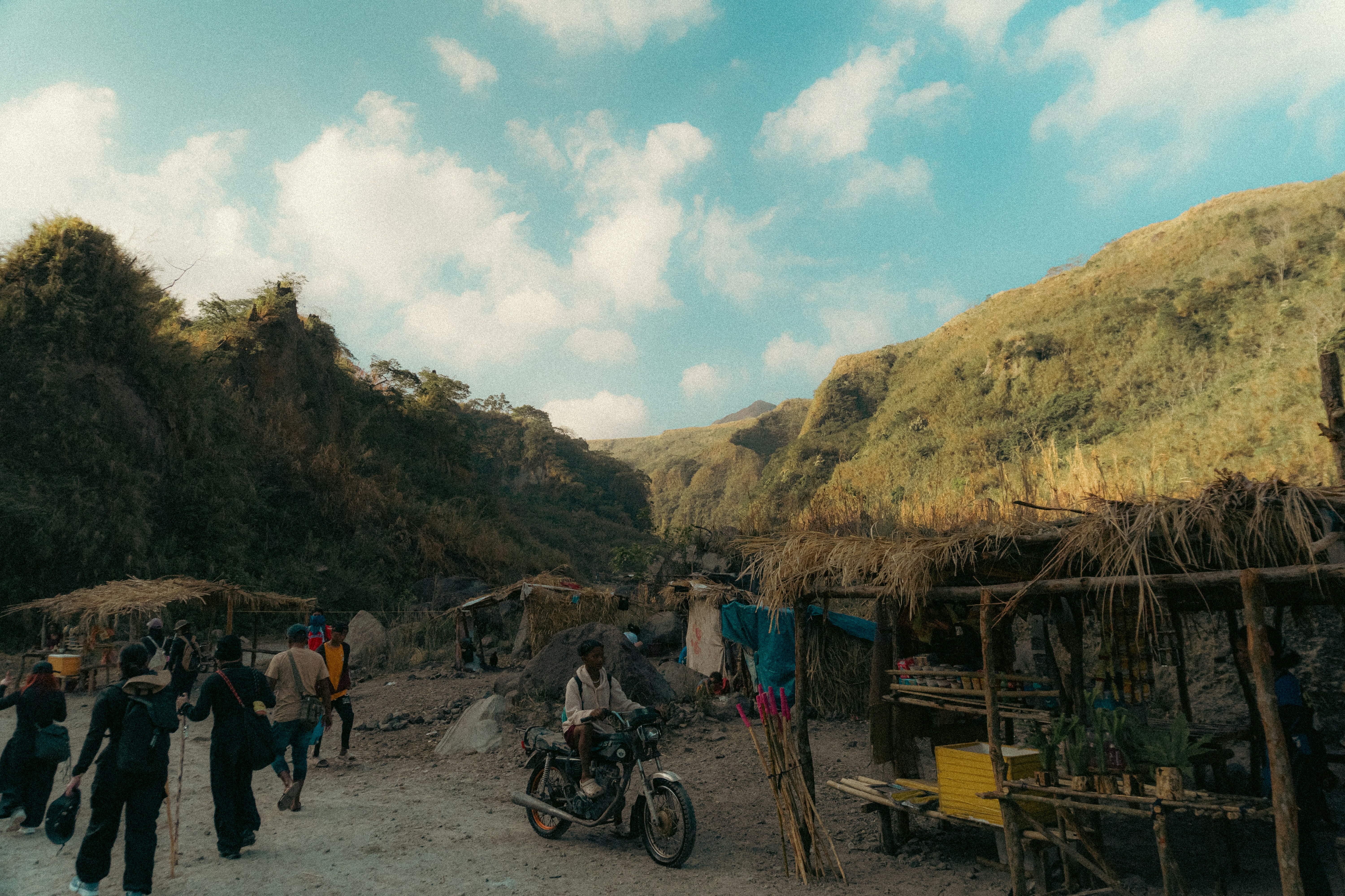 Dusty village street life under a widening blue sky