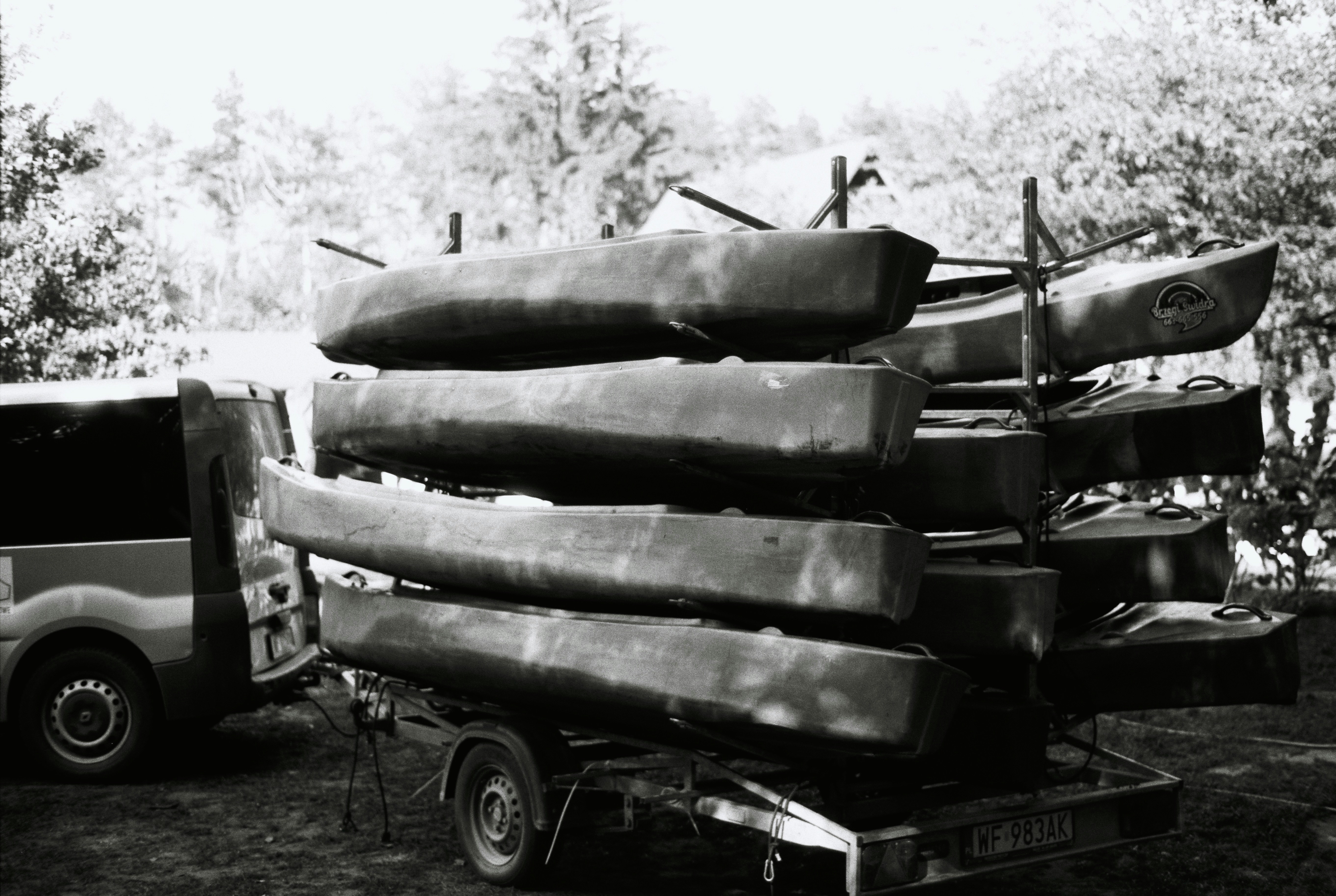 Stacked Canoes, Silent Truck: A Field of Boats and a Van