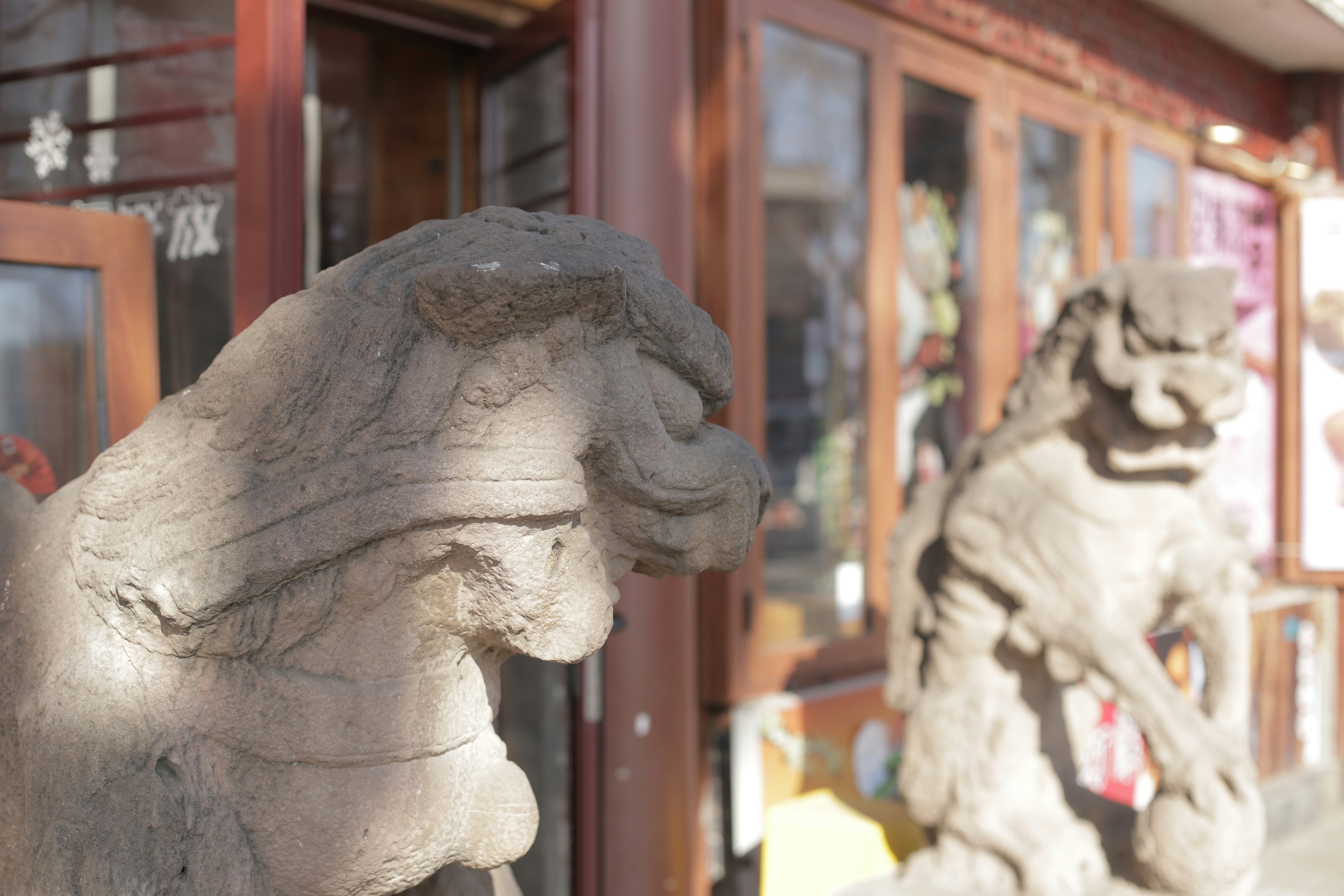 Grain and Granite Guardians: A Close-Up of the Stone Lions Before a Shopfront