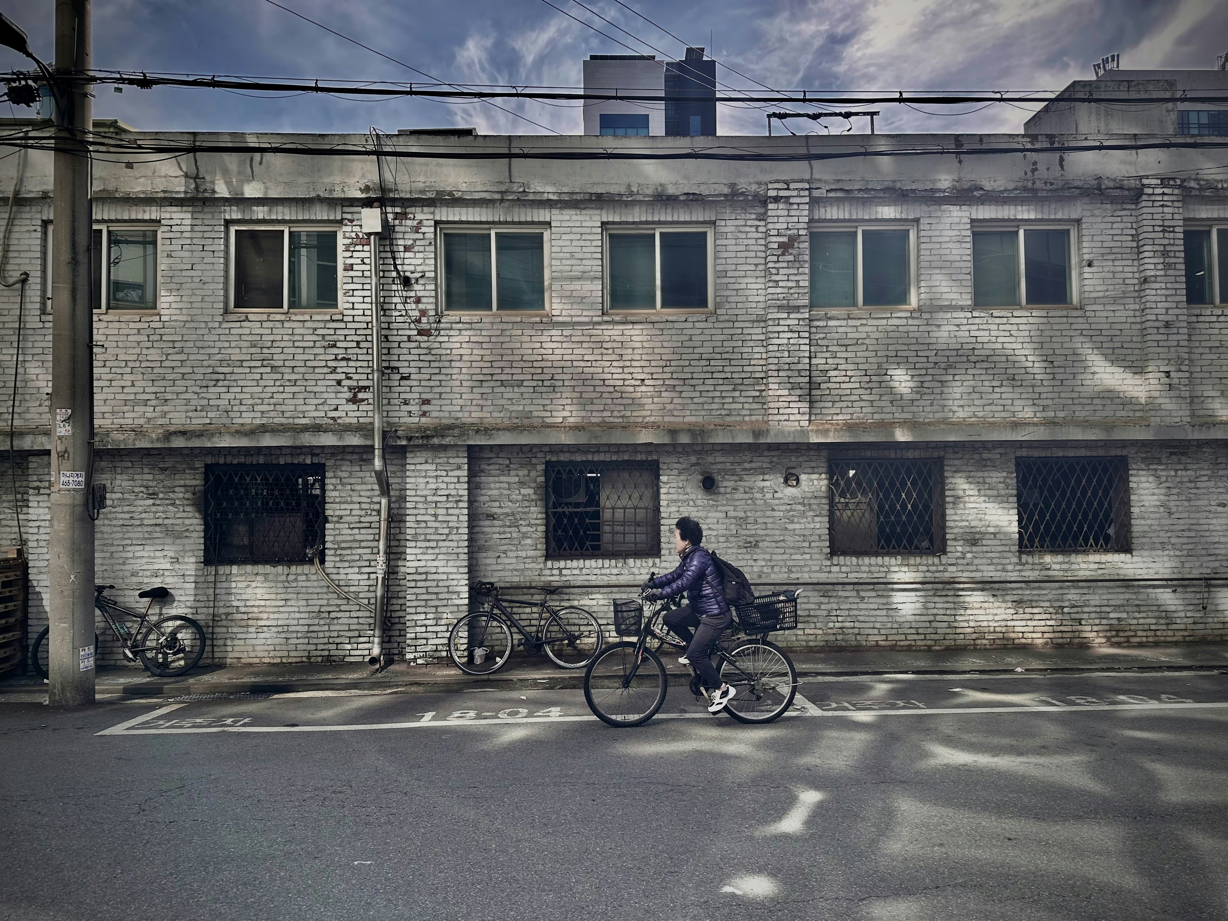 Rider in a Quiet Street: Steel-gray Facade, Autumn Light