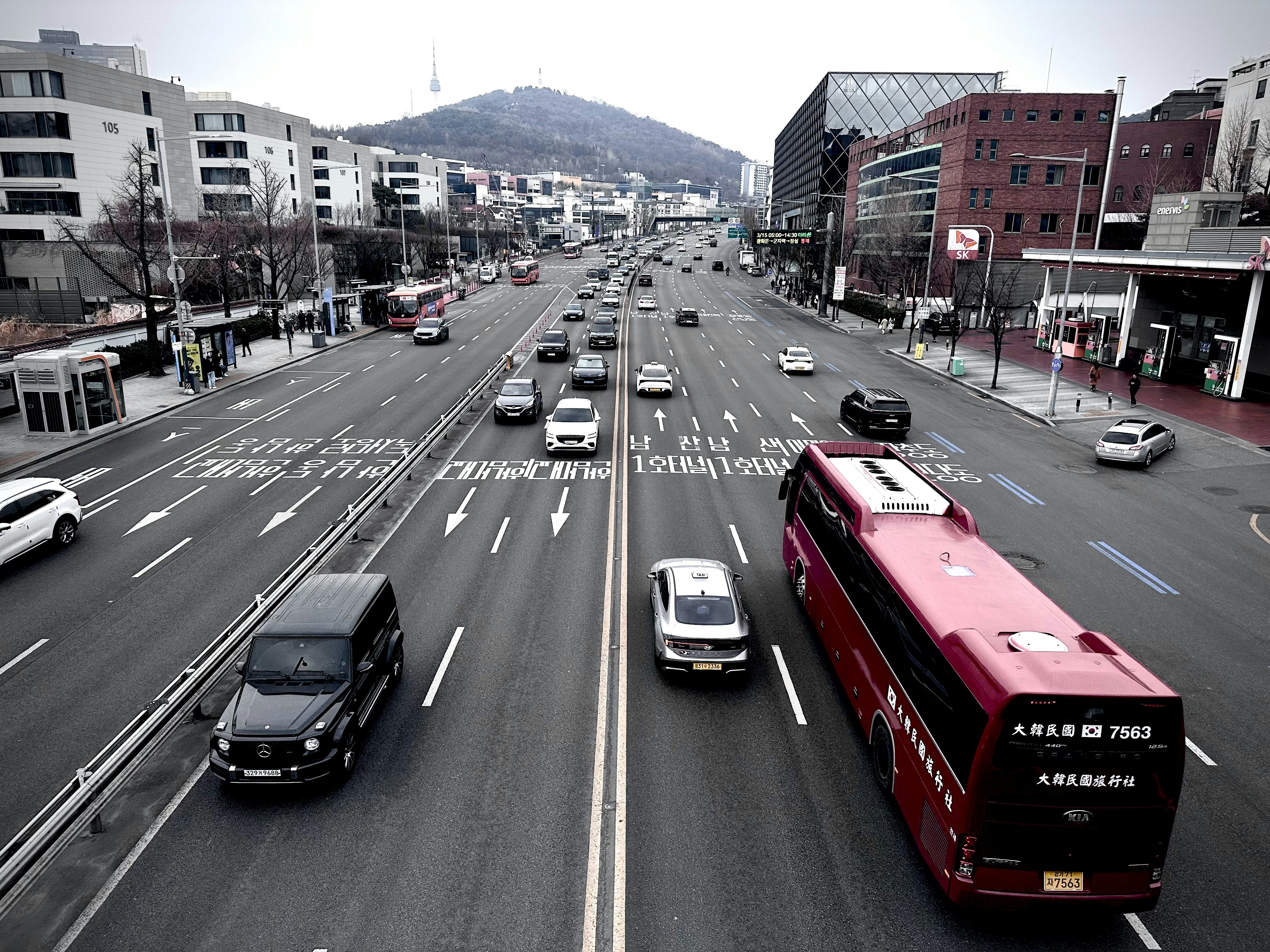Midday Shuffle: A Busy Urban Artery Framed by a Red Bus and Lanes of Traffic