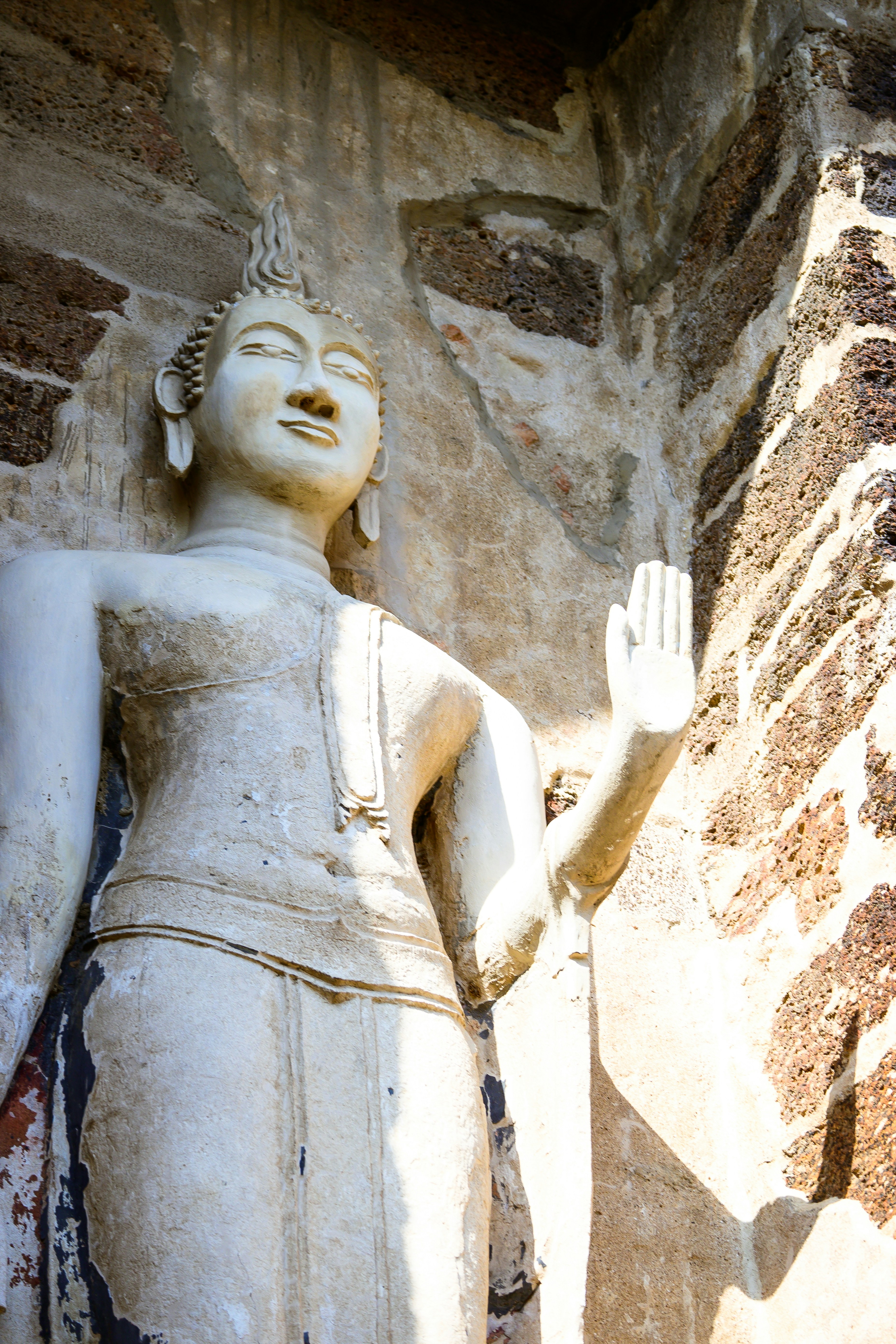 Silent Ascend: A Stone Buddha Behind Sunlit Stonework
