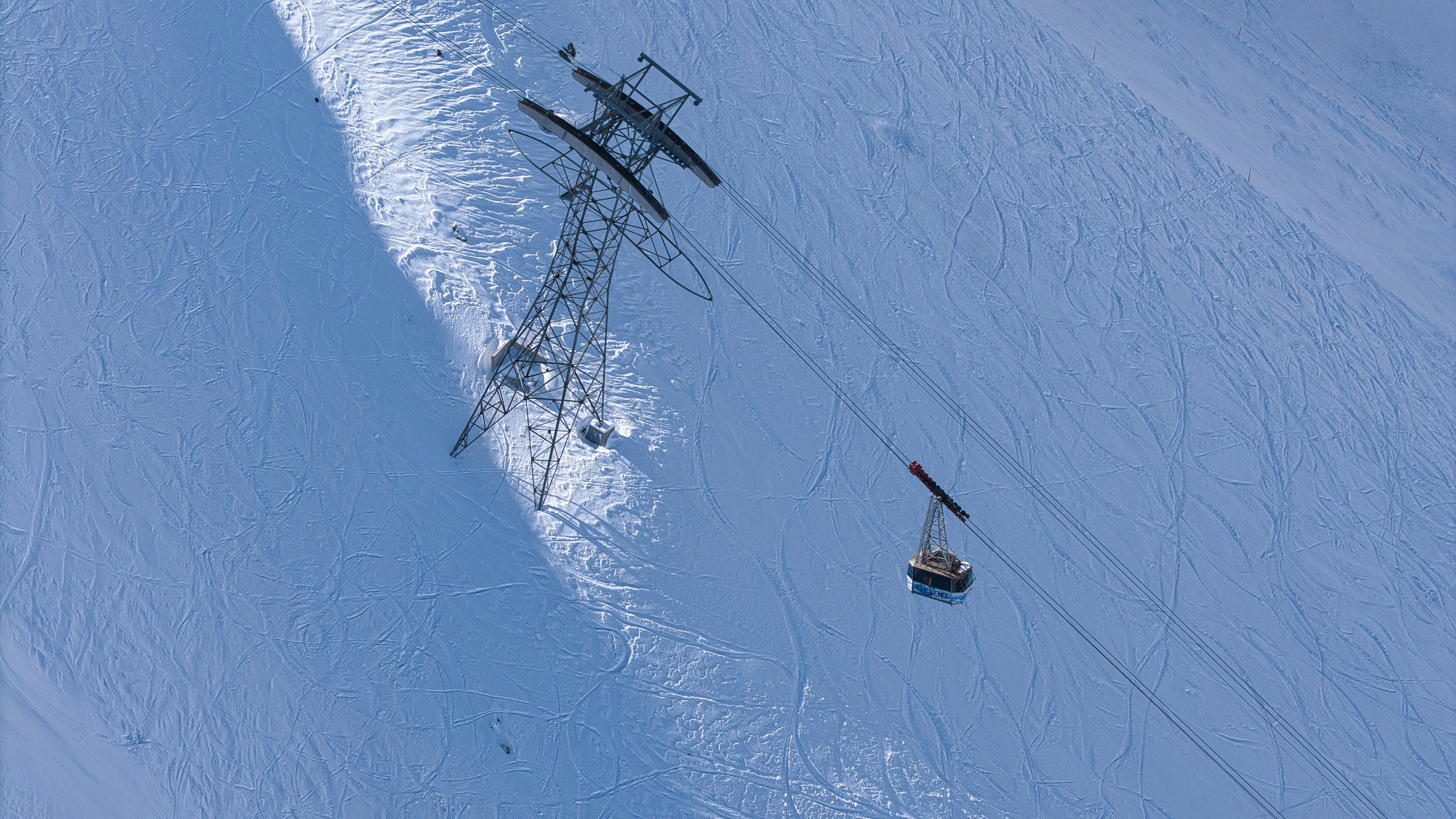 Glacier Cable Car Drift: Aerial View of Snow-Capped Ridge and Transmission Tower
