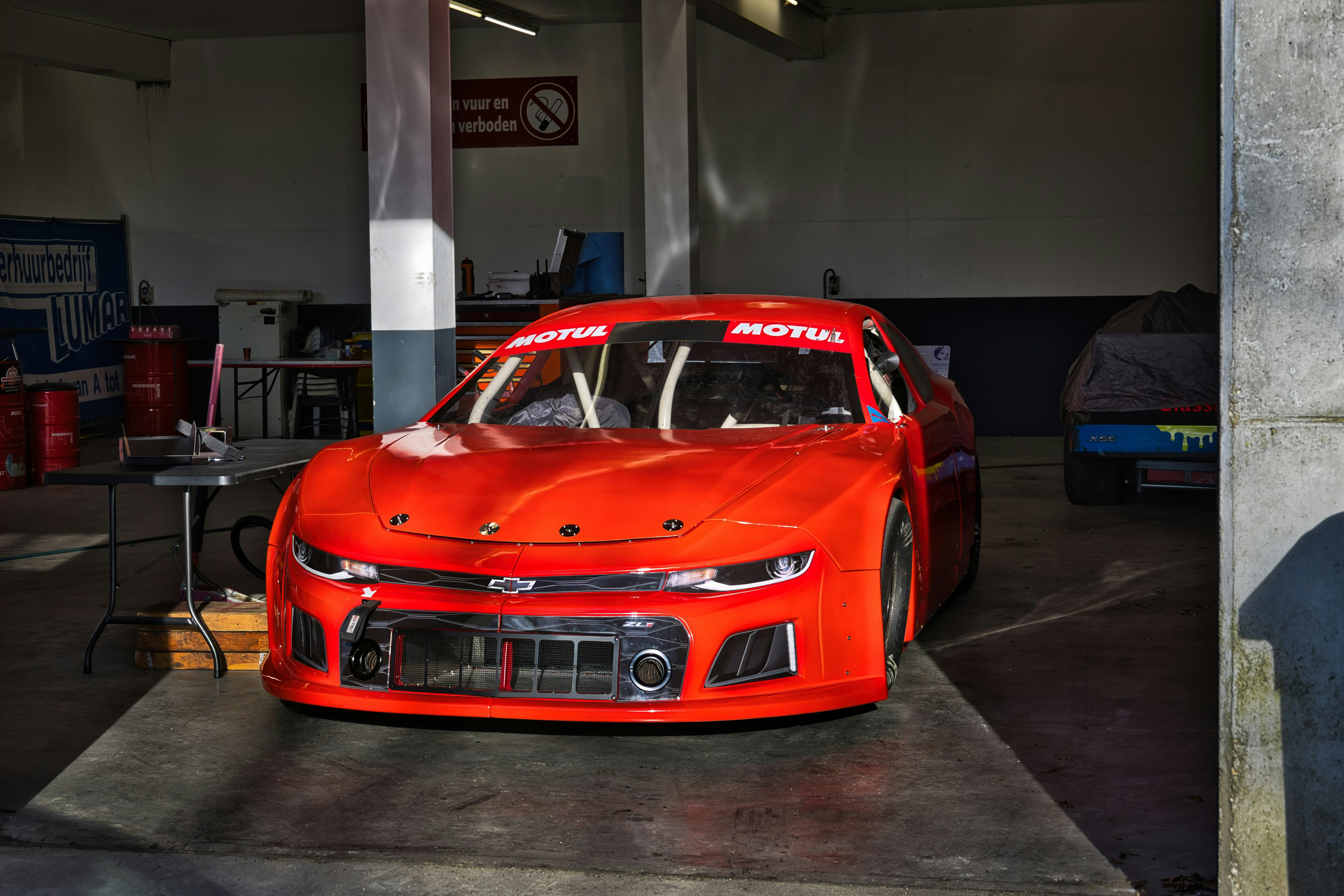 Red Racer in a Dim Garage: A Bold Stance by the Pit Door