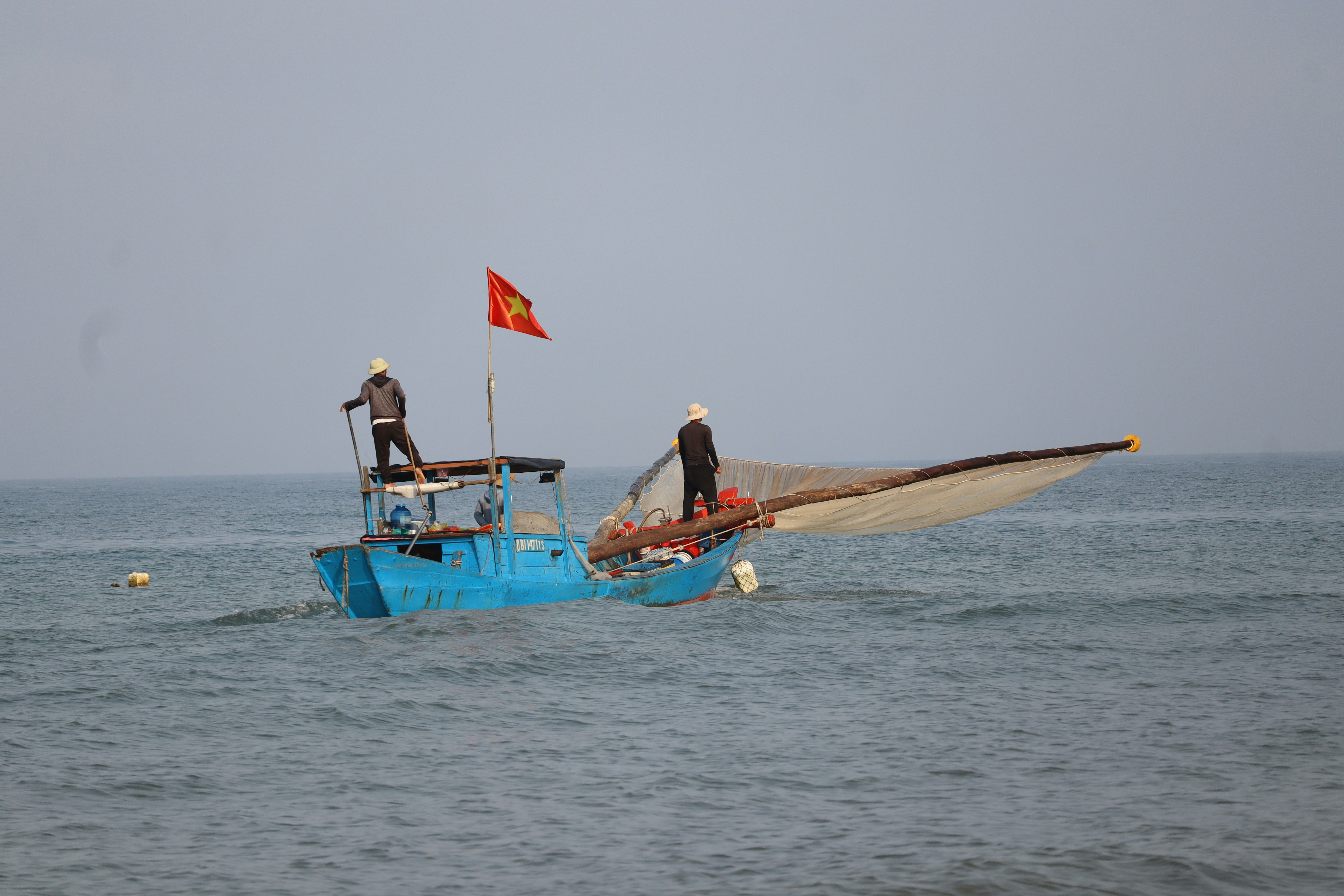 Blue Boat with Red Flag on Calm Sea