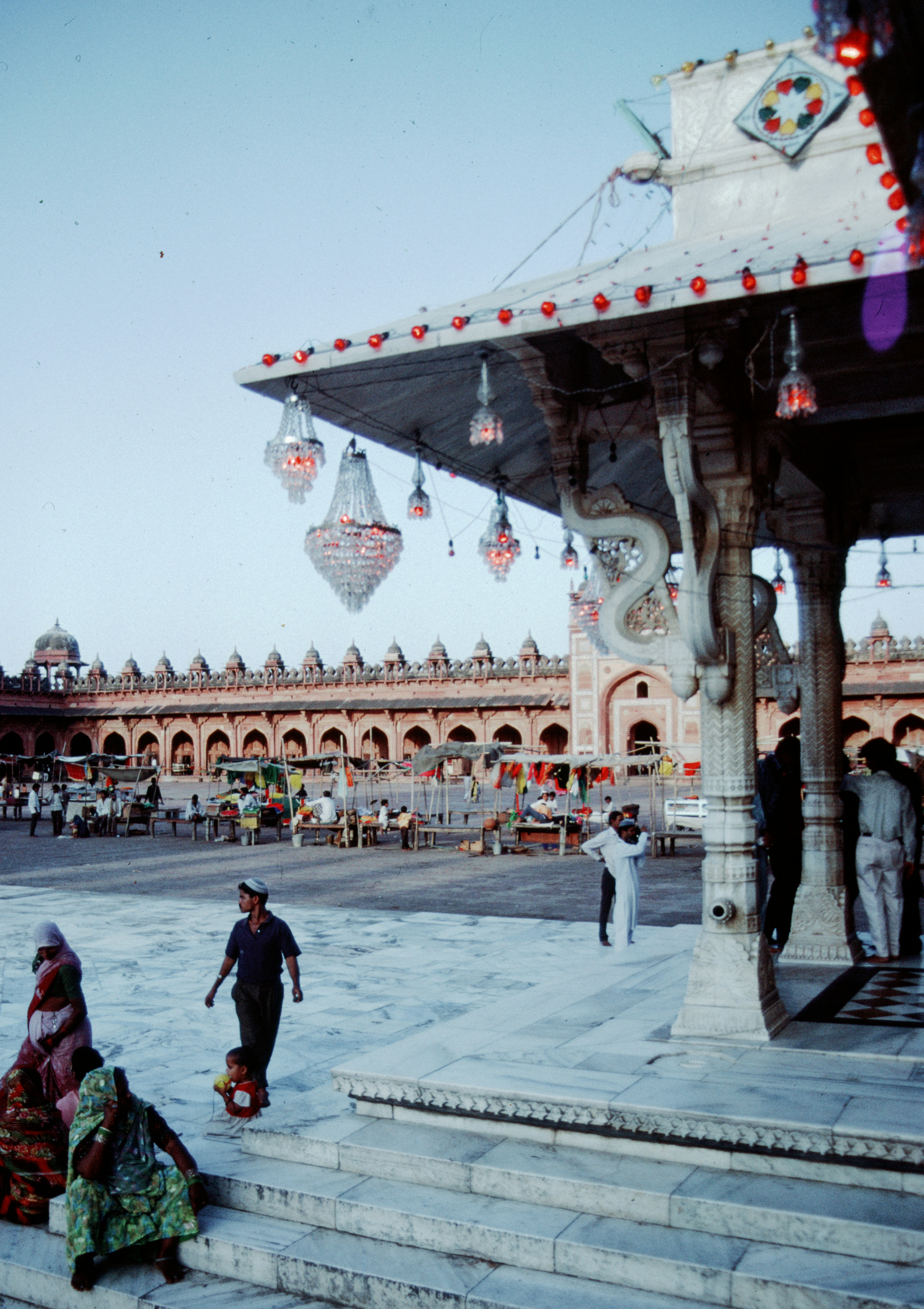 Temple Courtyard Echoes: People, Marble, and Lanterns at Hazy Dusk