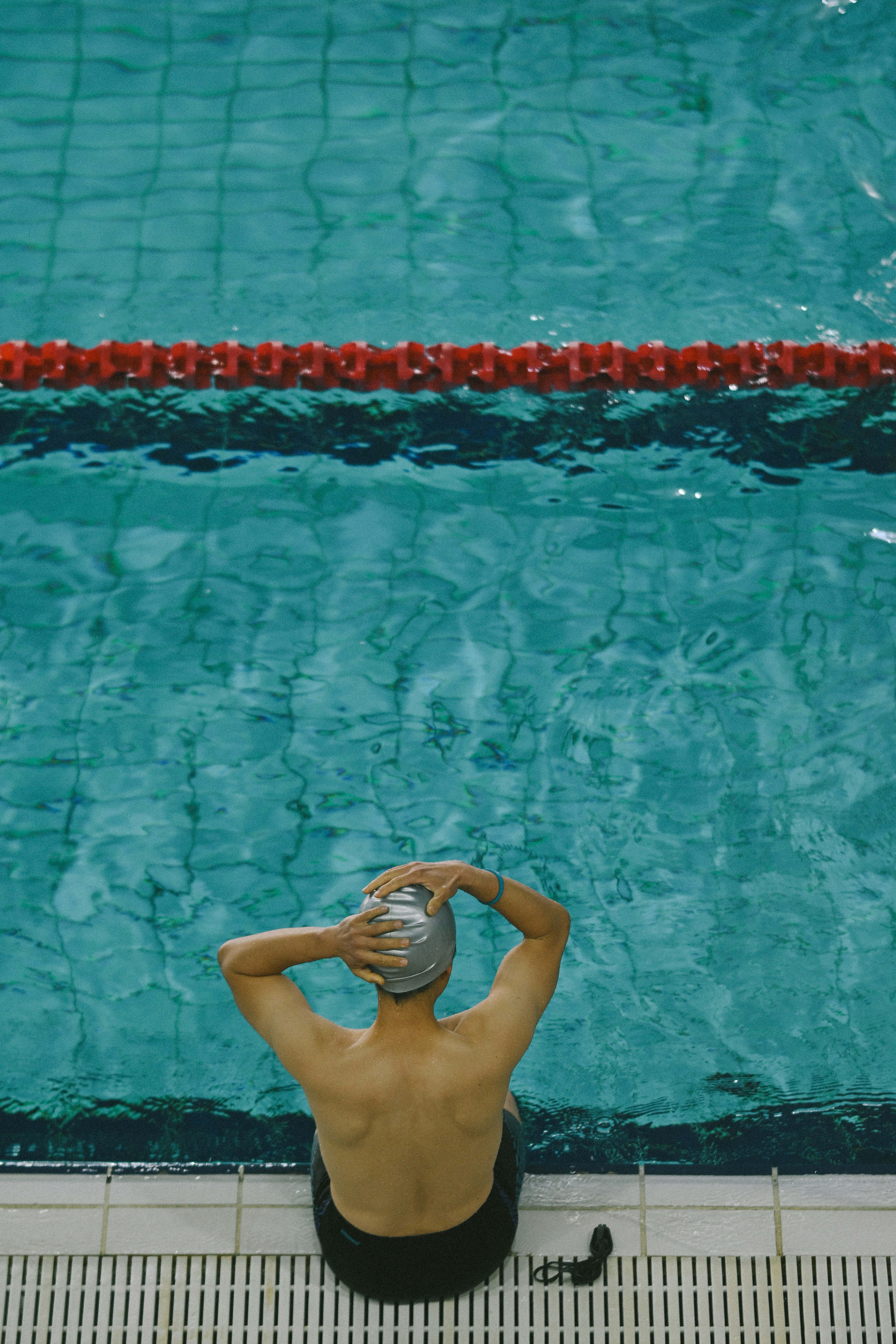 Watched by the Lane: A swimmer securing a moment of focus at the pool edge