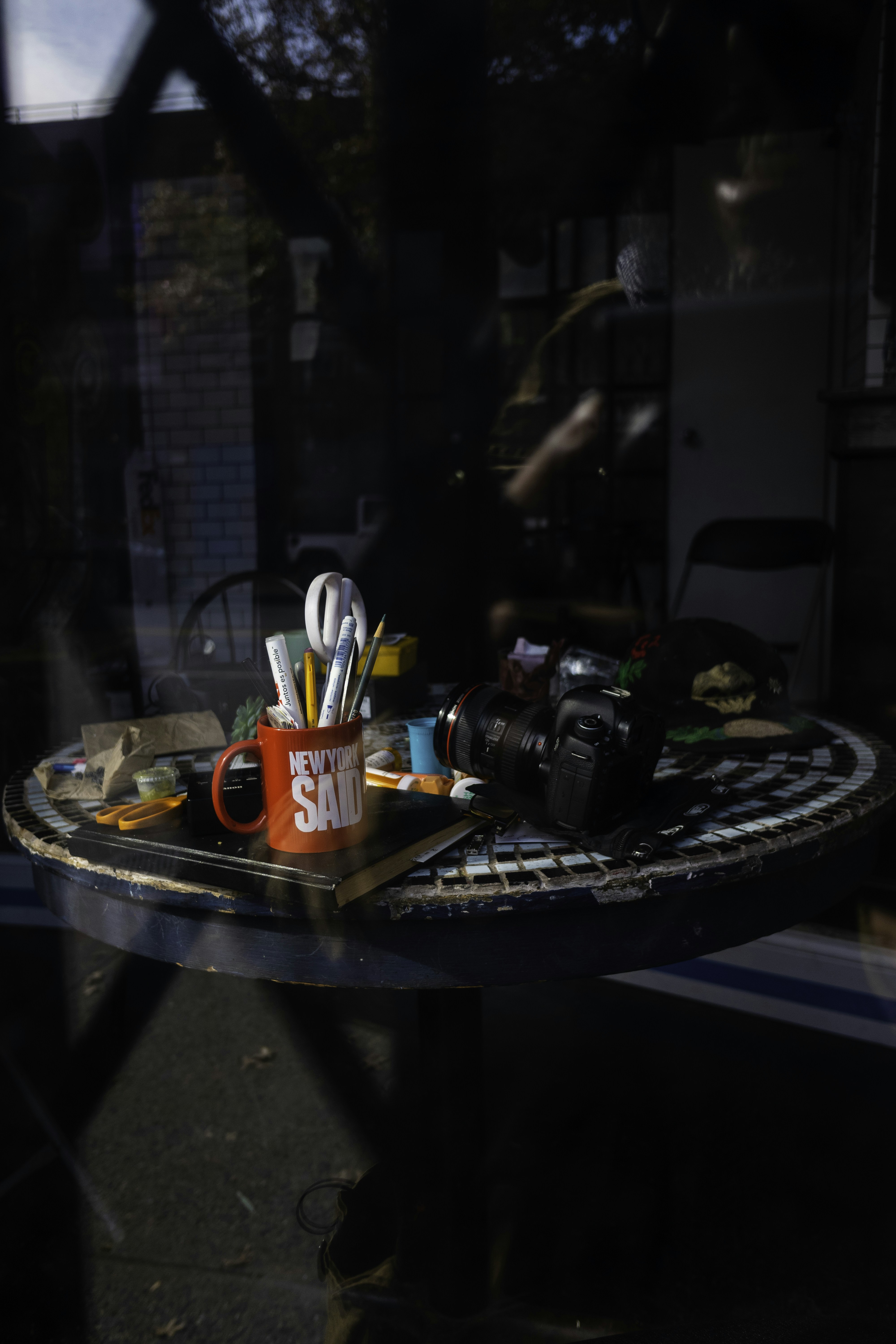Coffee mug, camera, and desk clutter under glass