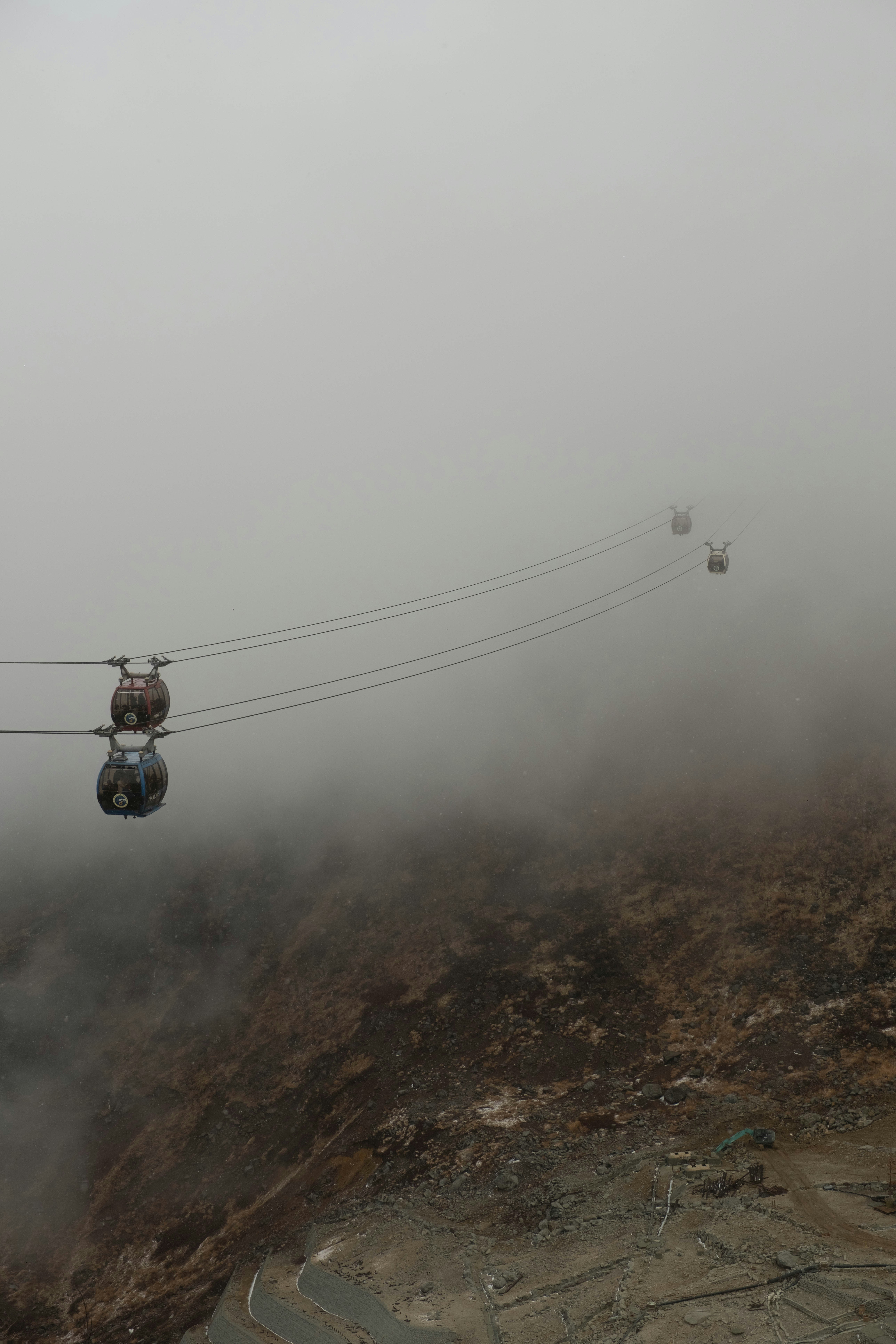 Cables through the Mist: A Fogbound Gondola Lift Traverses a Rugged Descent