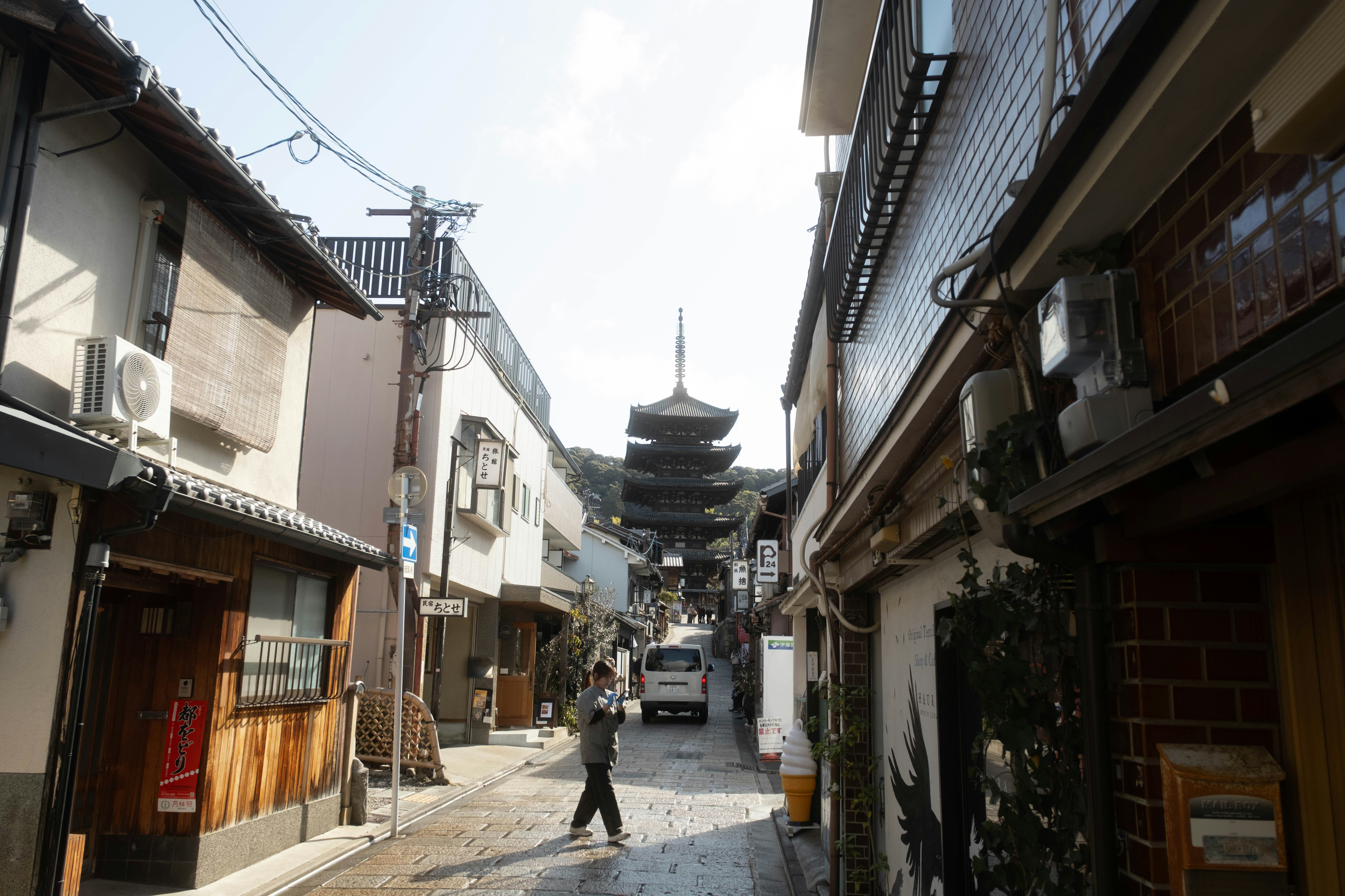 Temple framed by a quiet street: distant pagoda rising above traditional shops