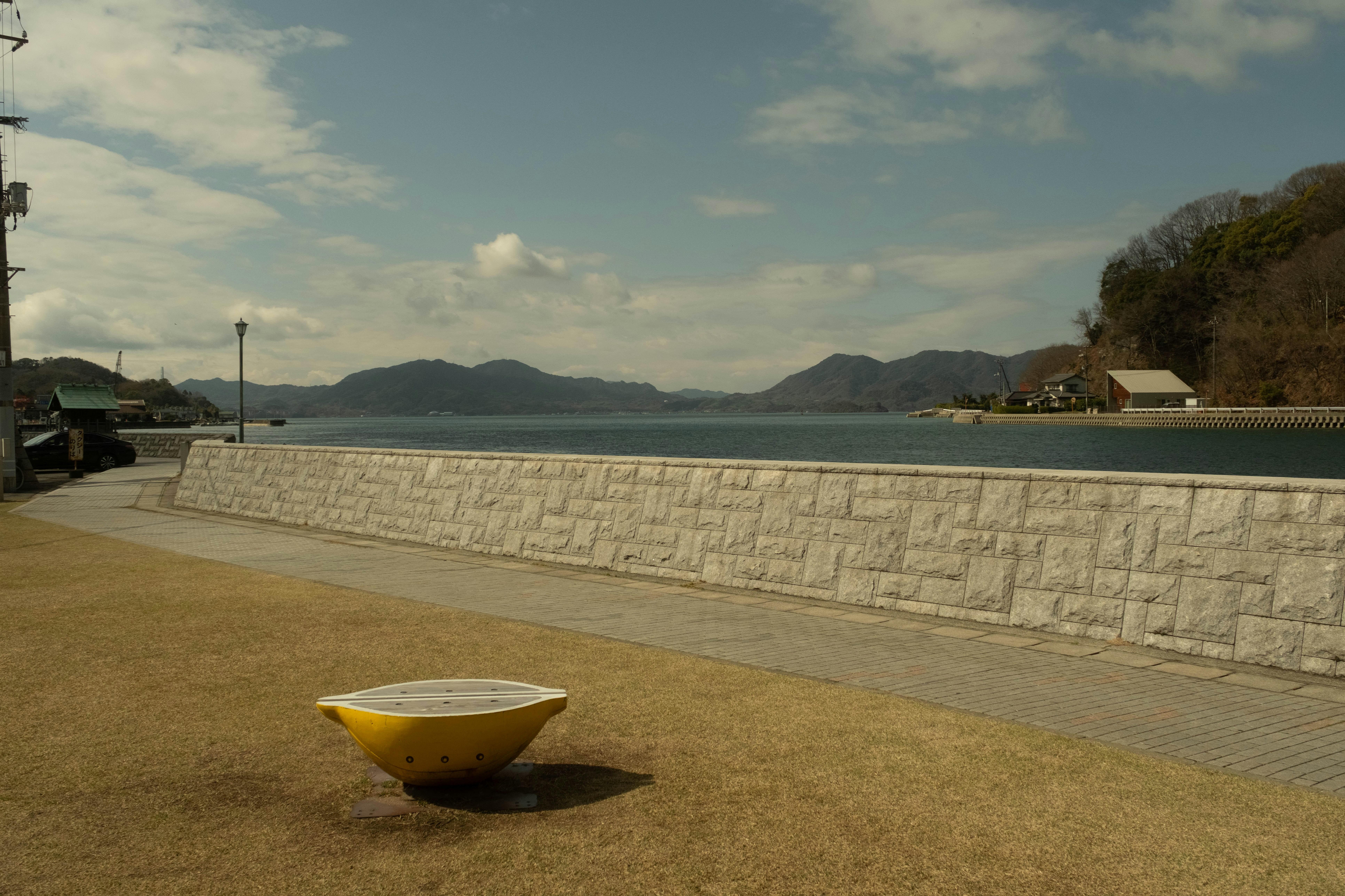 Yellow Boat Sculpt in a Seaside Park with Stone Sea Wall