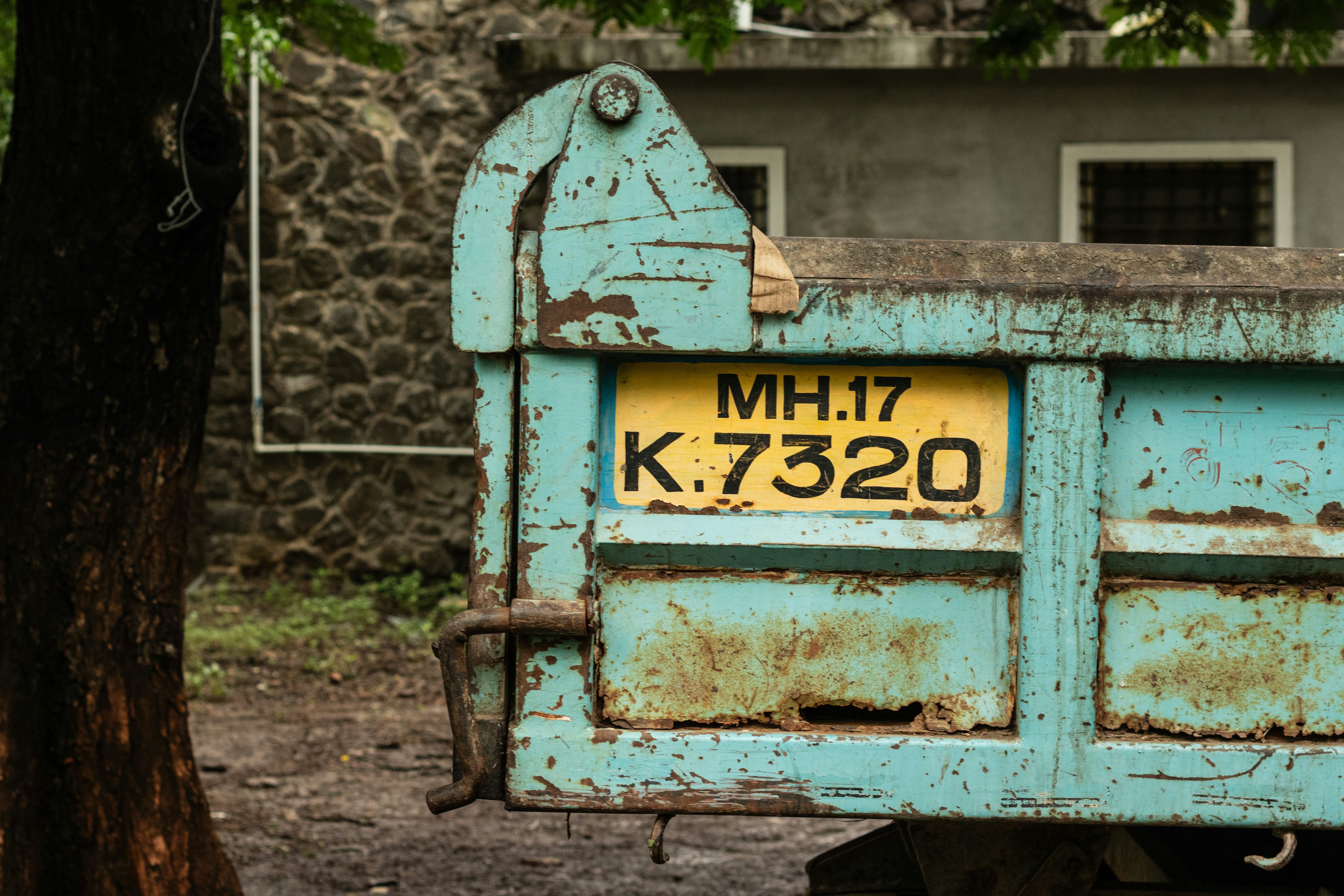 Weathered turquoise trailer lid with bold license plate in a quiet courtyard