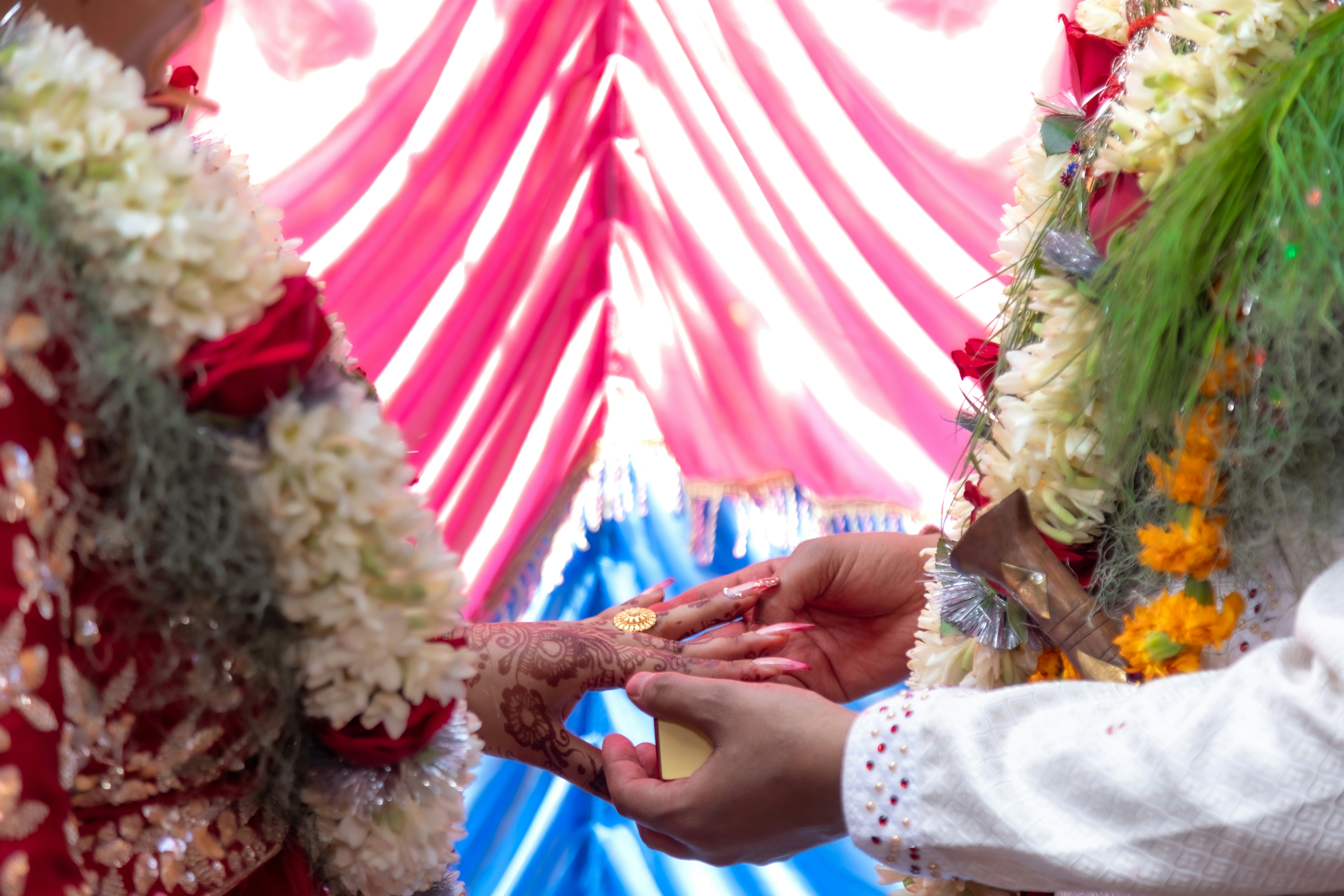 Bride and groom exchanging rings amid vibrant drapery