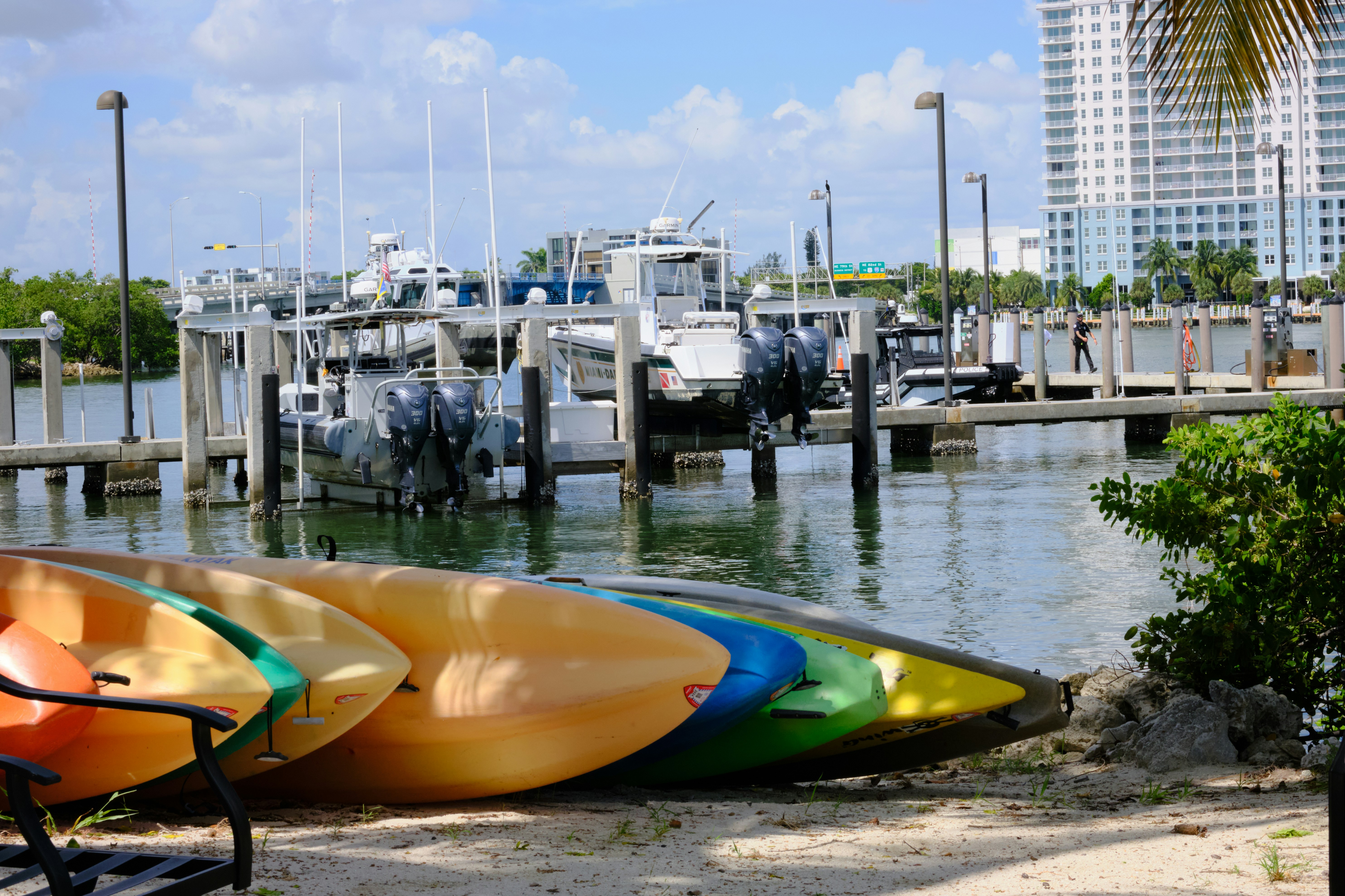 Colorful Kayaks Rest at Shore as Boats Slip into Marina Light