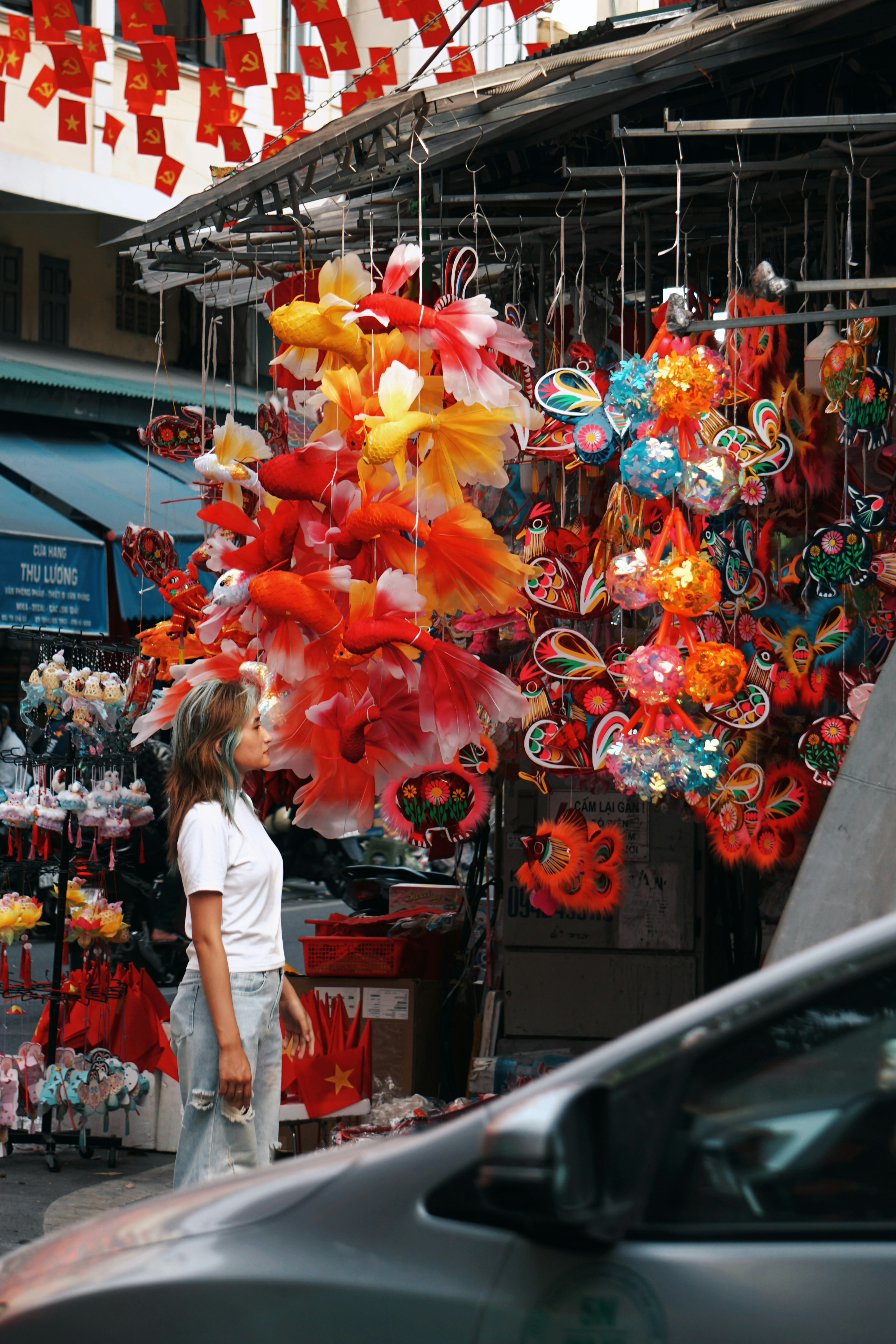 Market stall of vibrant handmade ribbons and toys frames a lone shopper