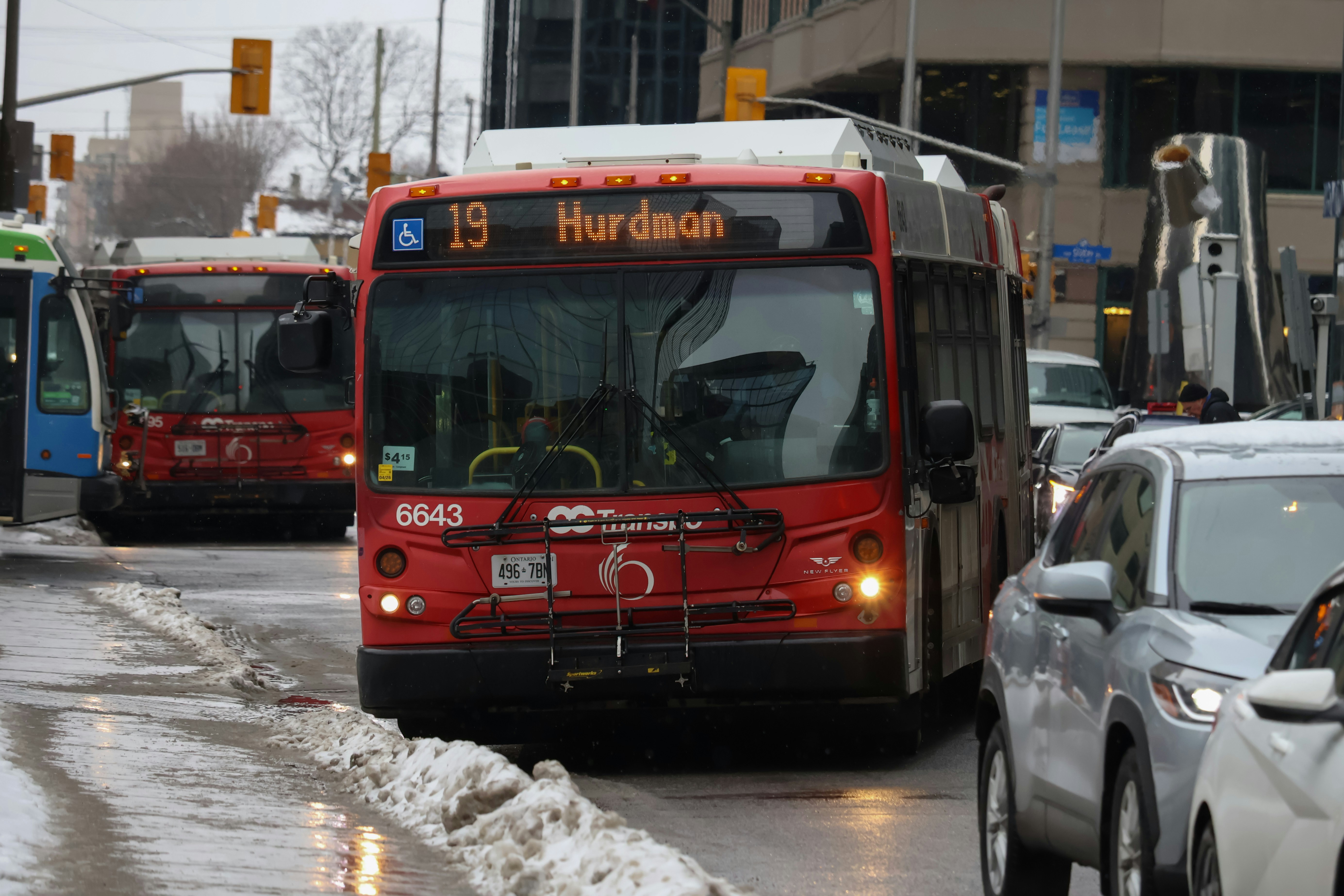 Red City Bus Navigates a Wet Corridor Amid Traffic