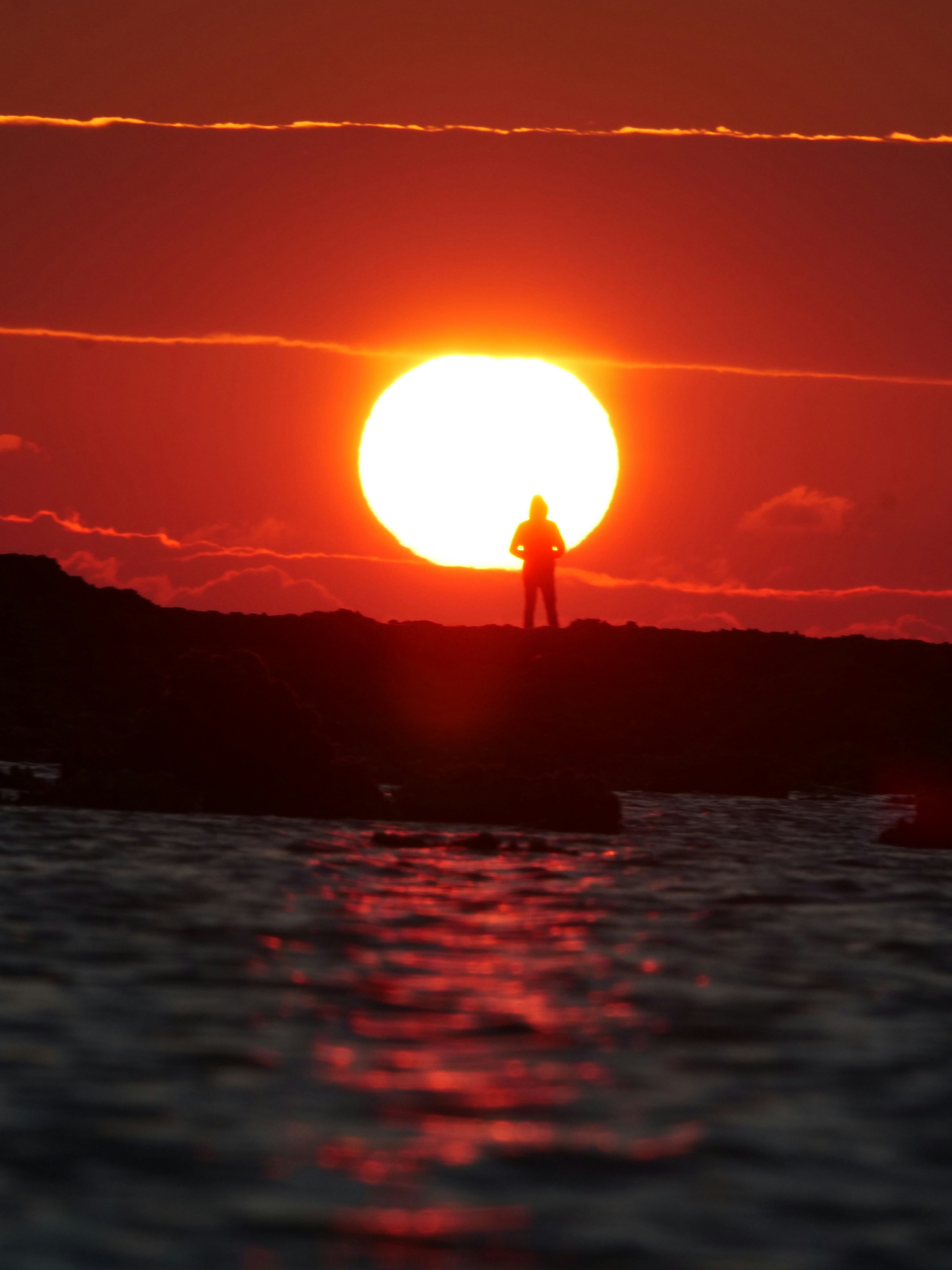 Sunlit Silhouette: A Lone Figure on a Tidal Ridge at Dusk