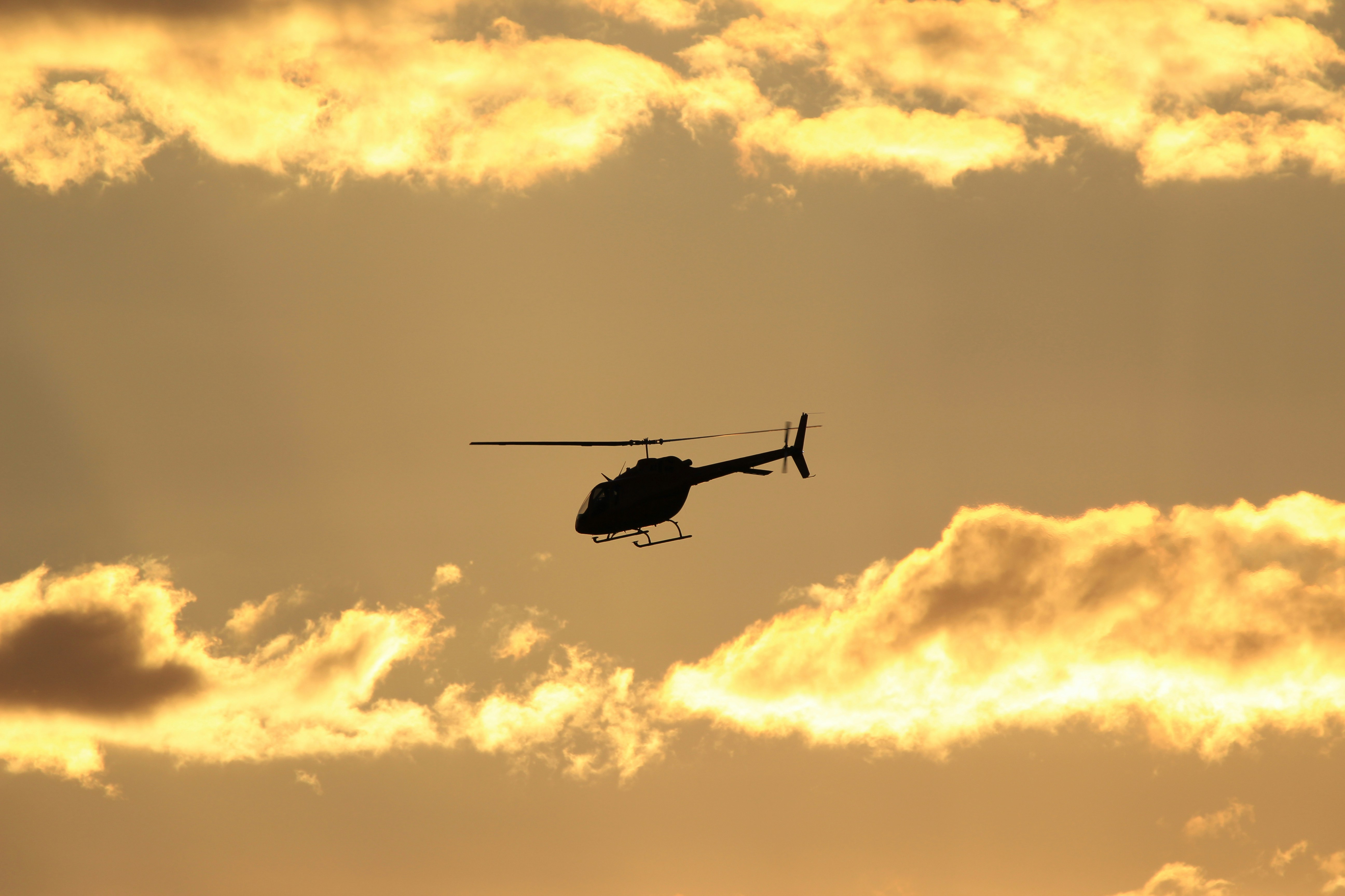 Silhouette Over Golden Skies: A Helicopter in Twilight Flight