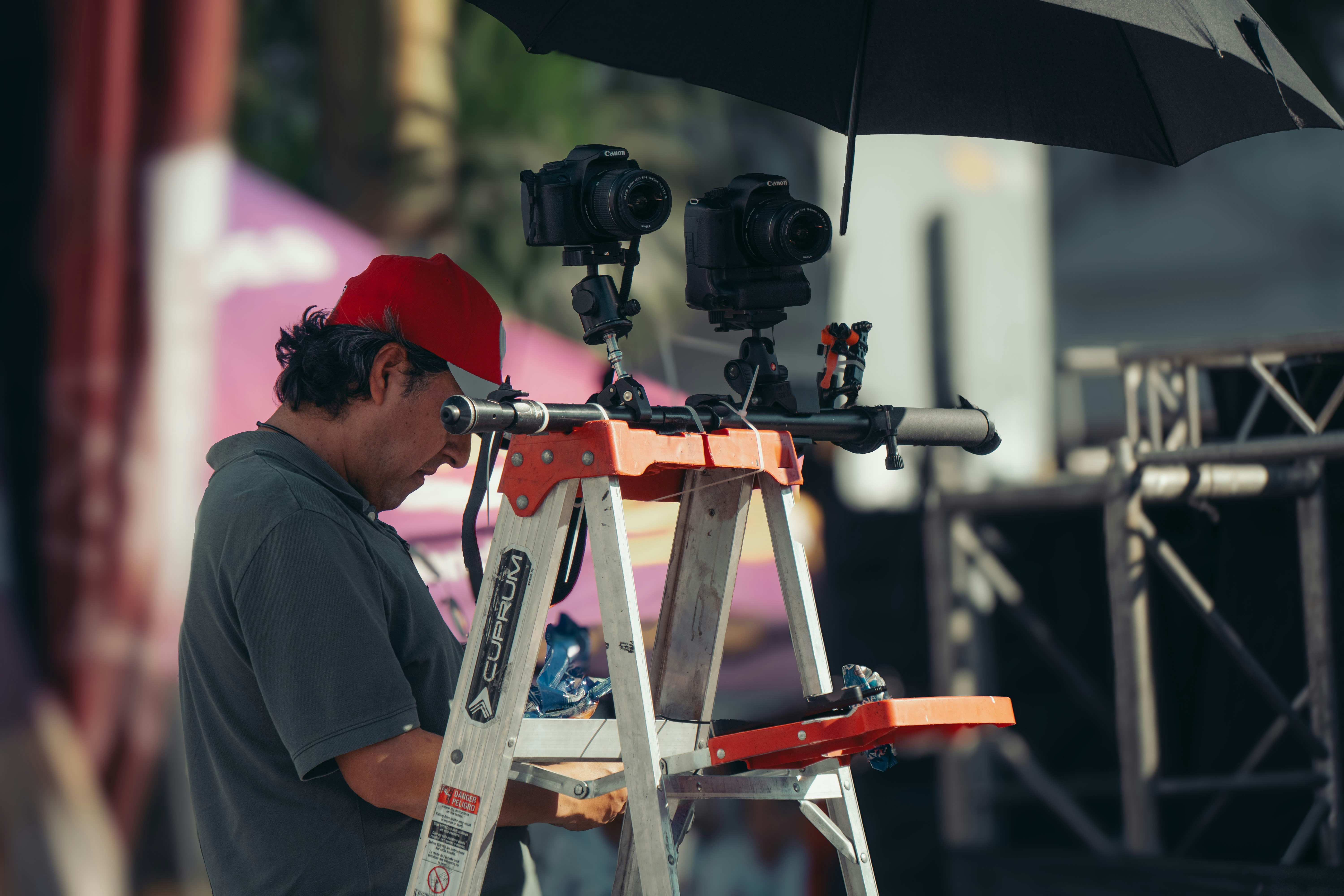 Crew Member Aligns Double Camera Rig on a Ladder at a Stage