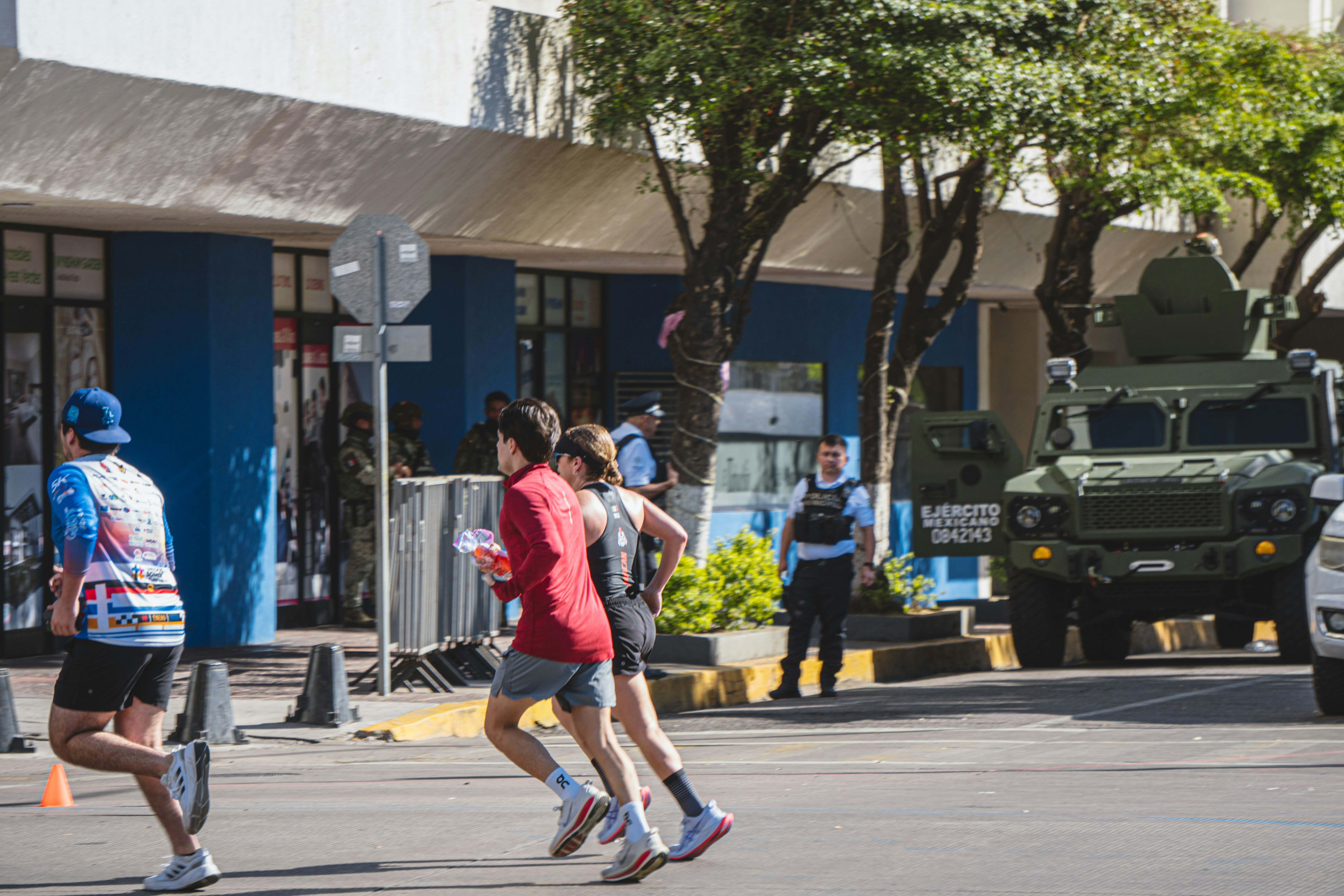 Sprint in the Shade: Runners Dash Past a Tactical Vehicle
