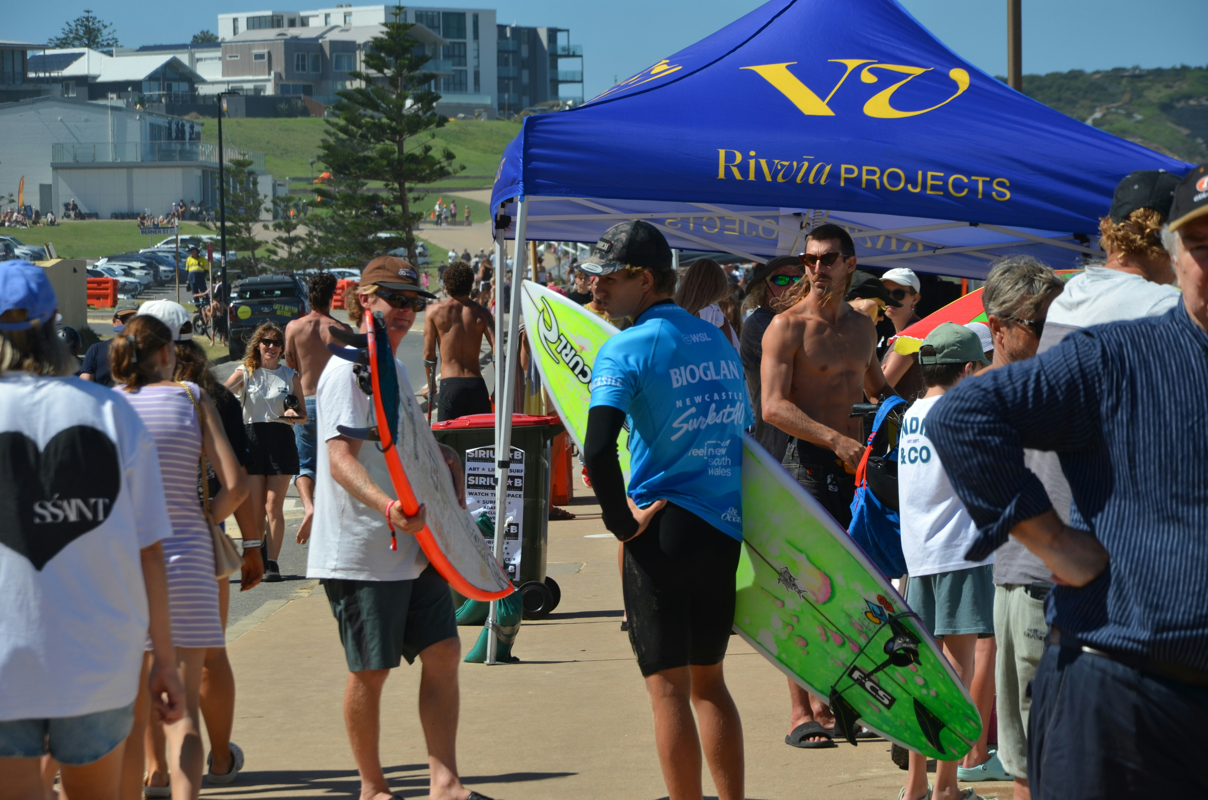 Crowd at a sunny surf gear booth with a vivid blue canopy