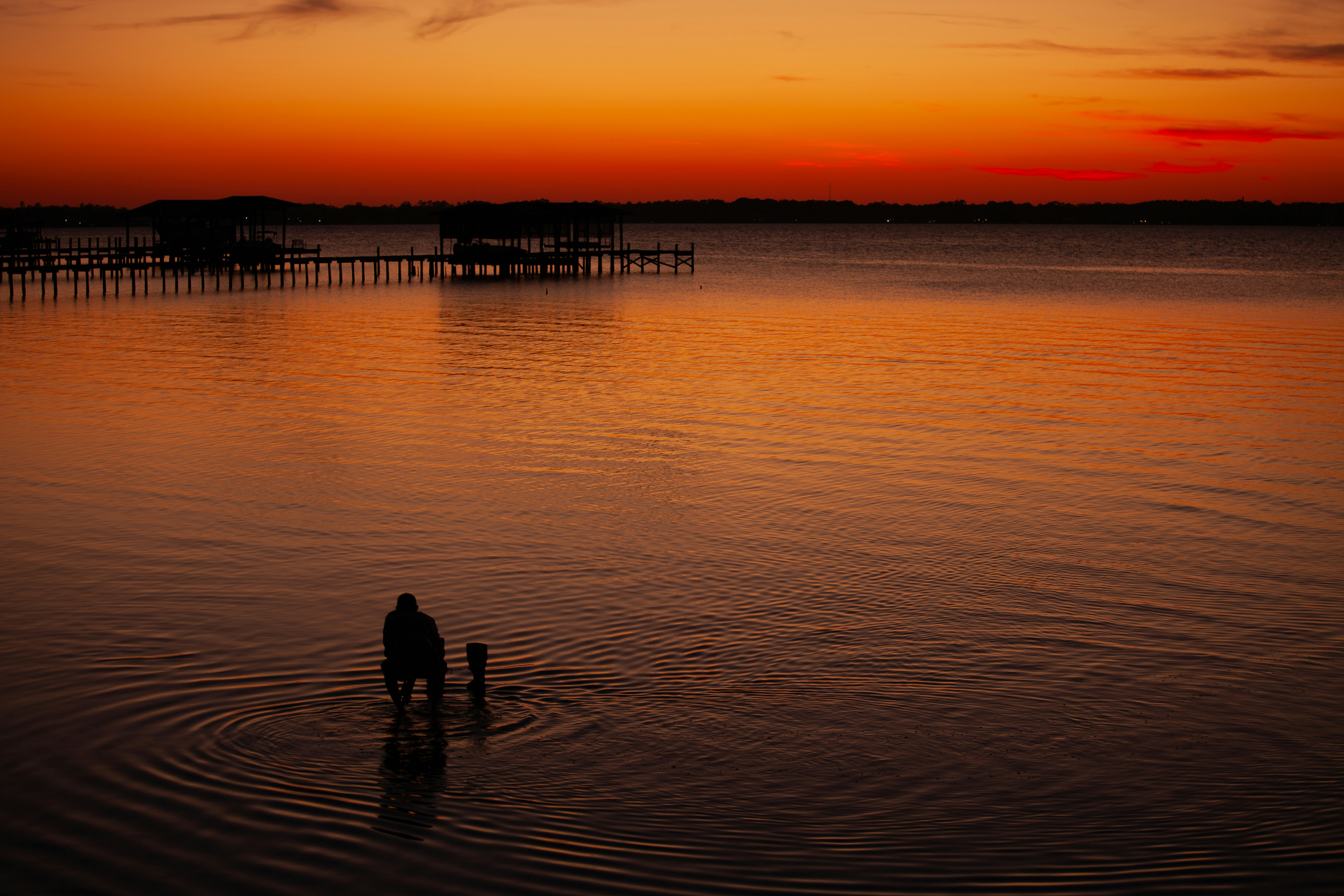 Silhouettes at Dusk: A Quiet Dip by the Distant Pier