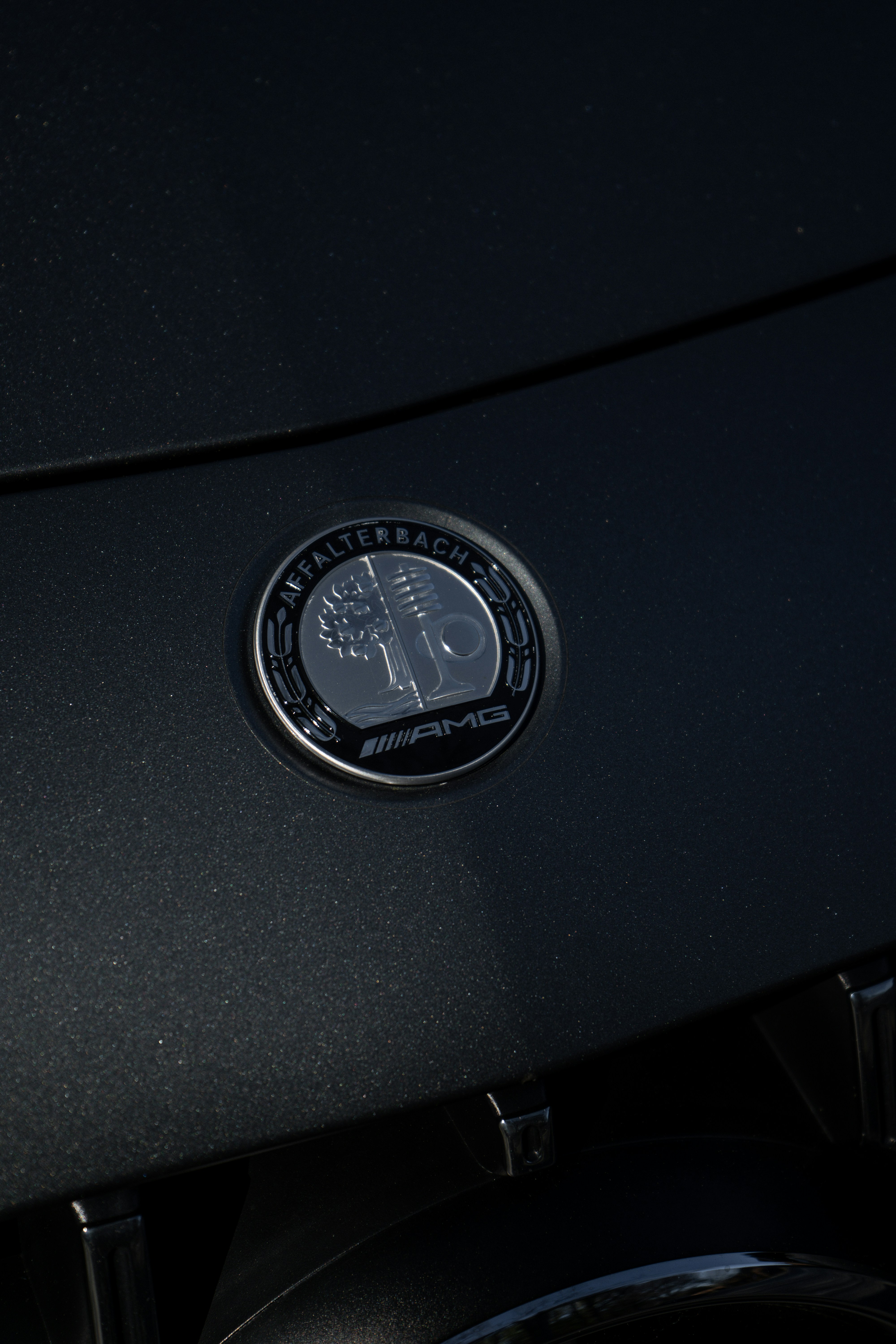 AMG emblem on a dark metallic surface beneath a subtle arc of light