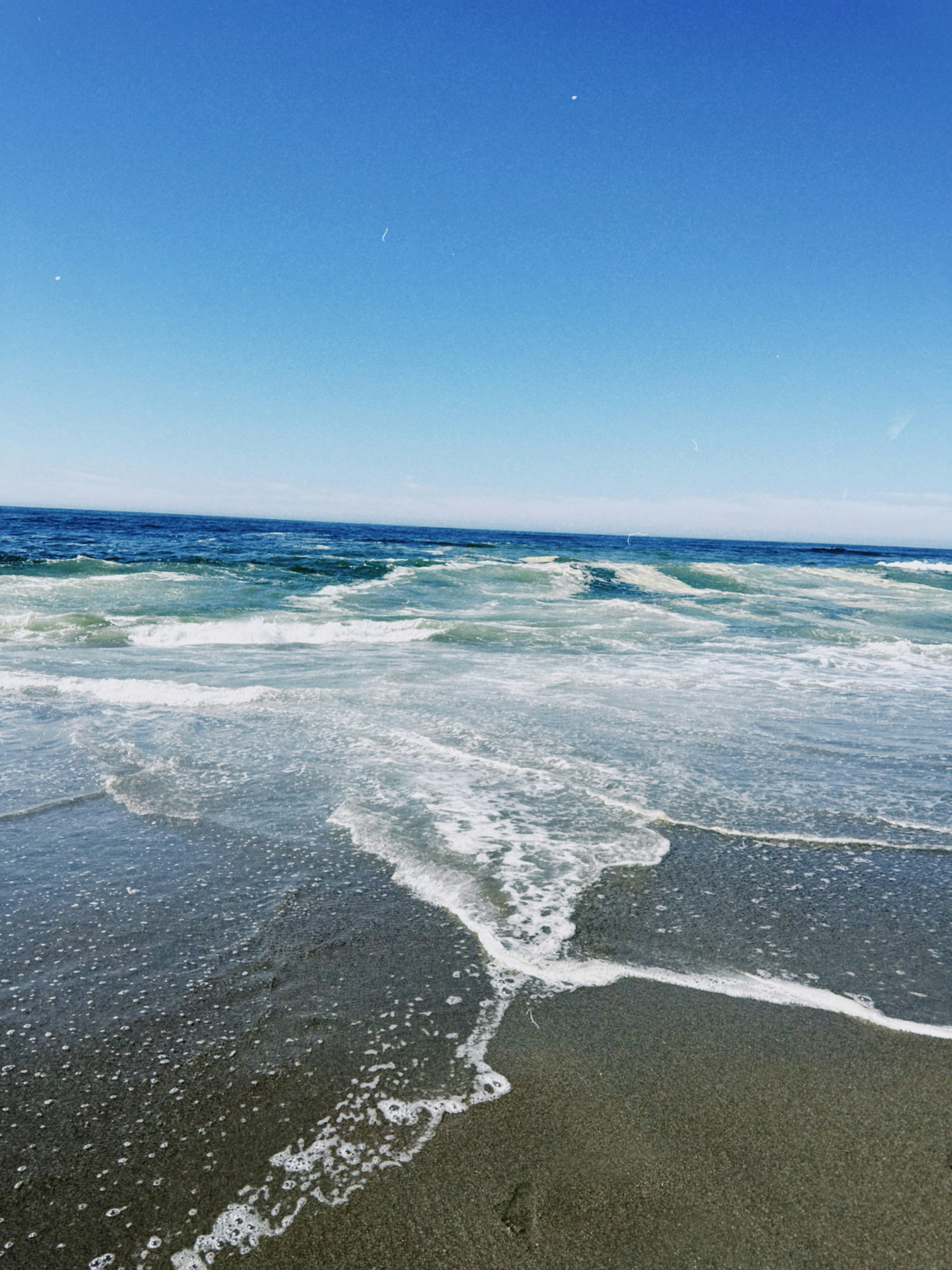 A Quiet Horizon: Waves Meet Wet Sand at Dusk on a Seaside Shore