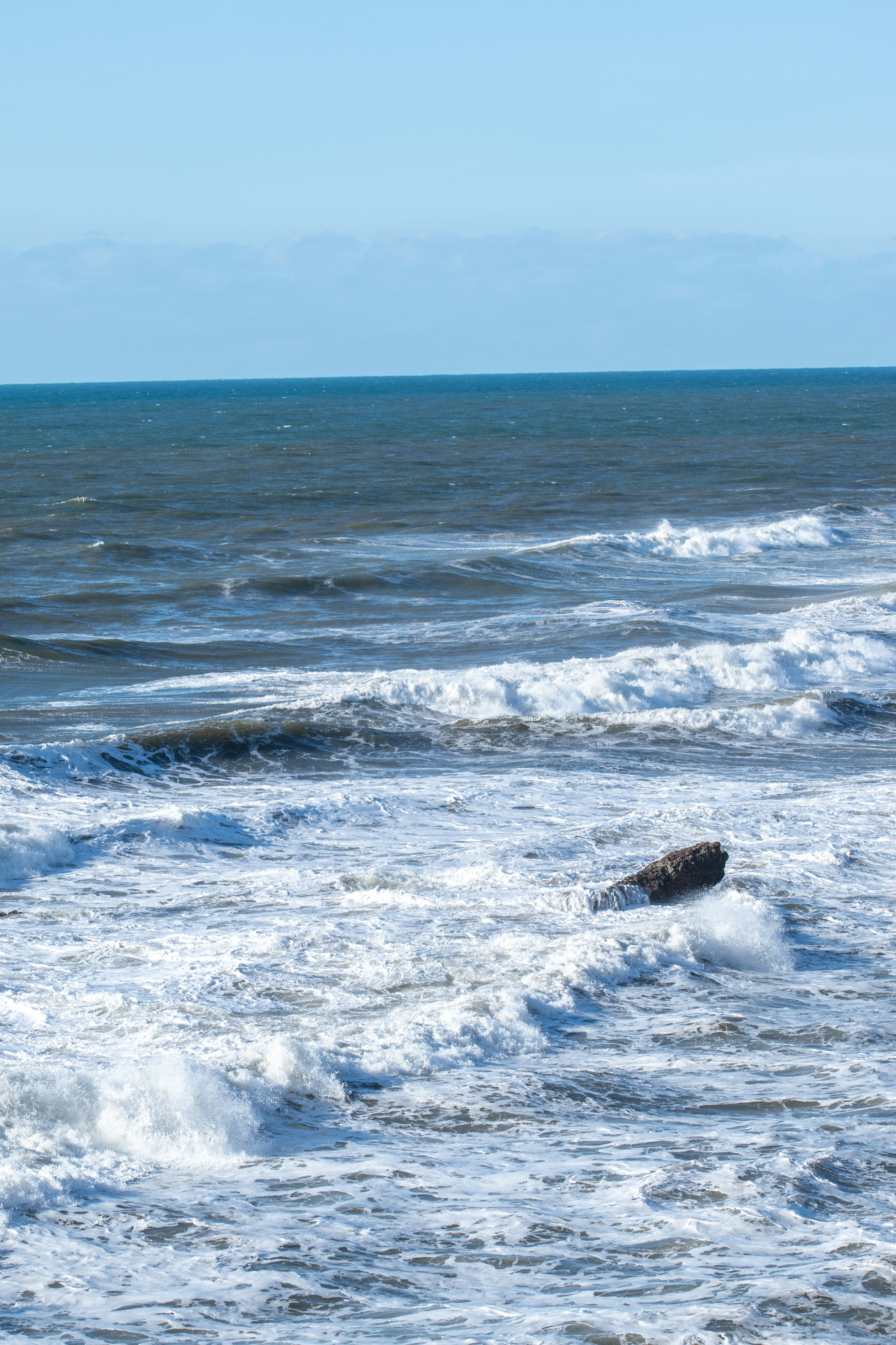 Coastal Surge: A lone wave break against weathered shoreline