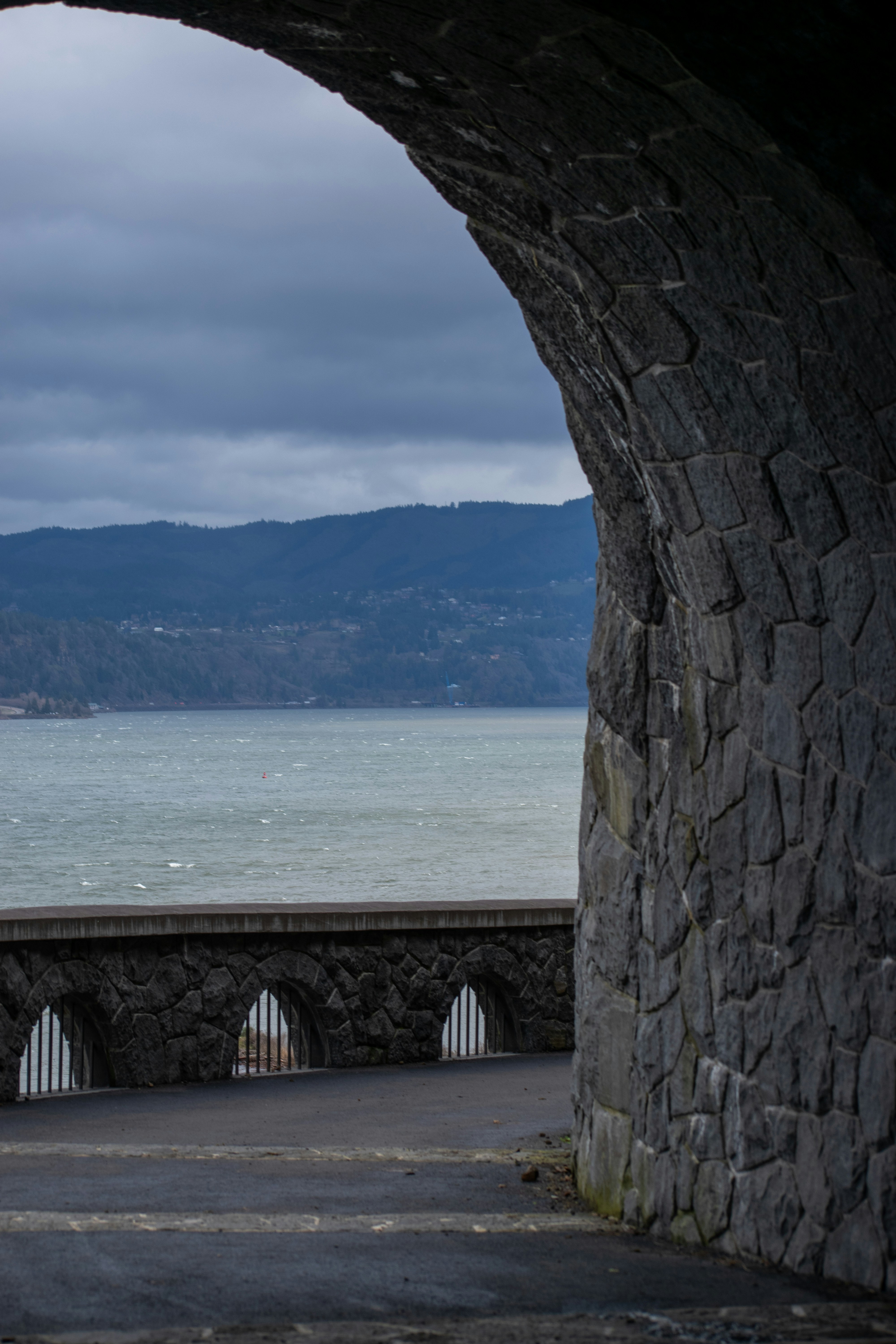 Stone archway overlooking a choppy gray ocean and hills
