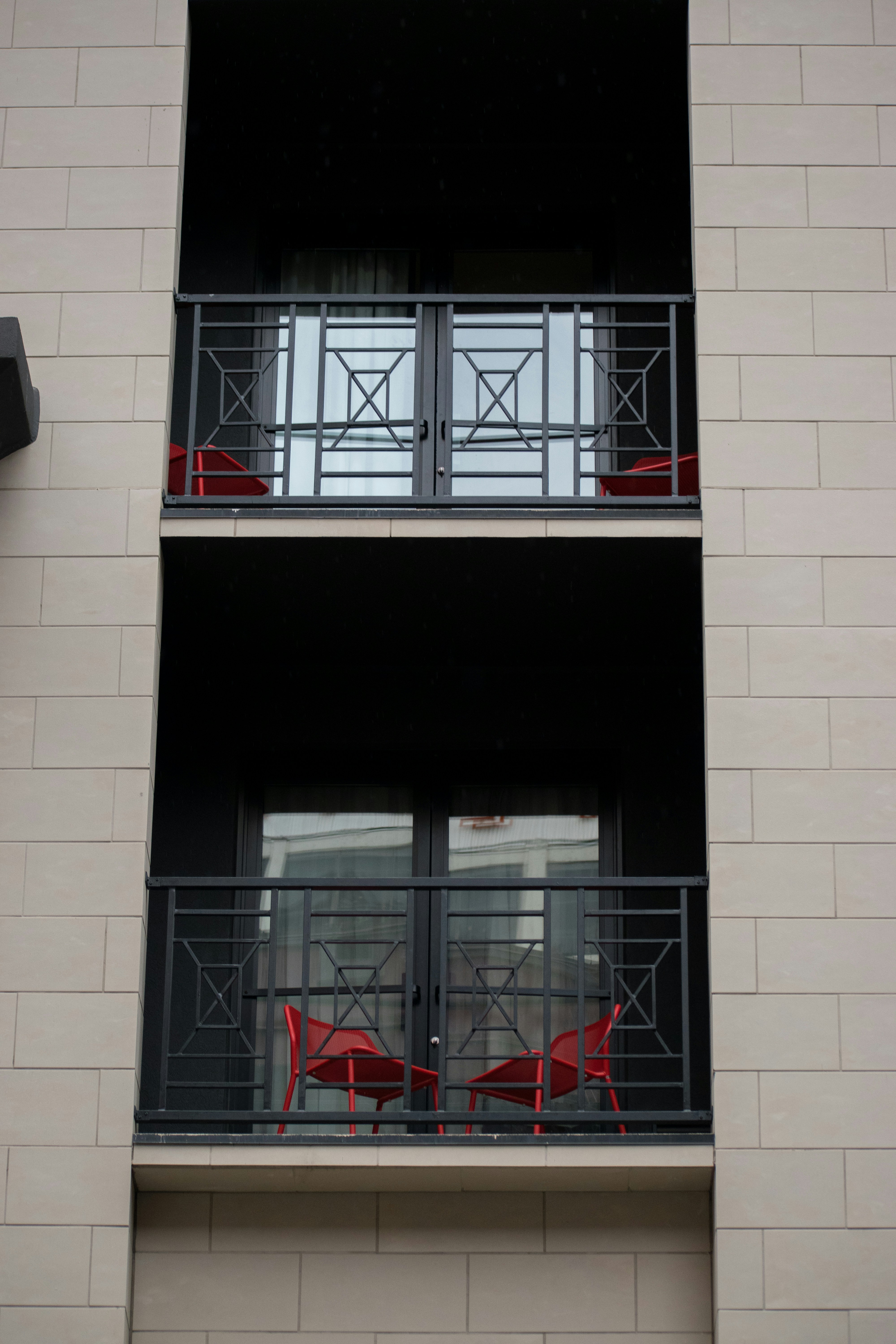 Red Chairs on Geometric Balcony: A Vertical Modern Facade