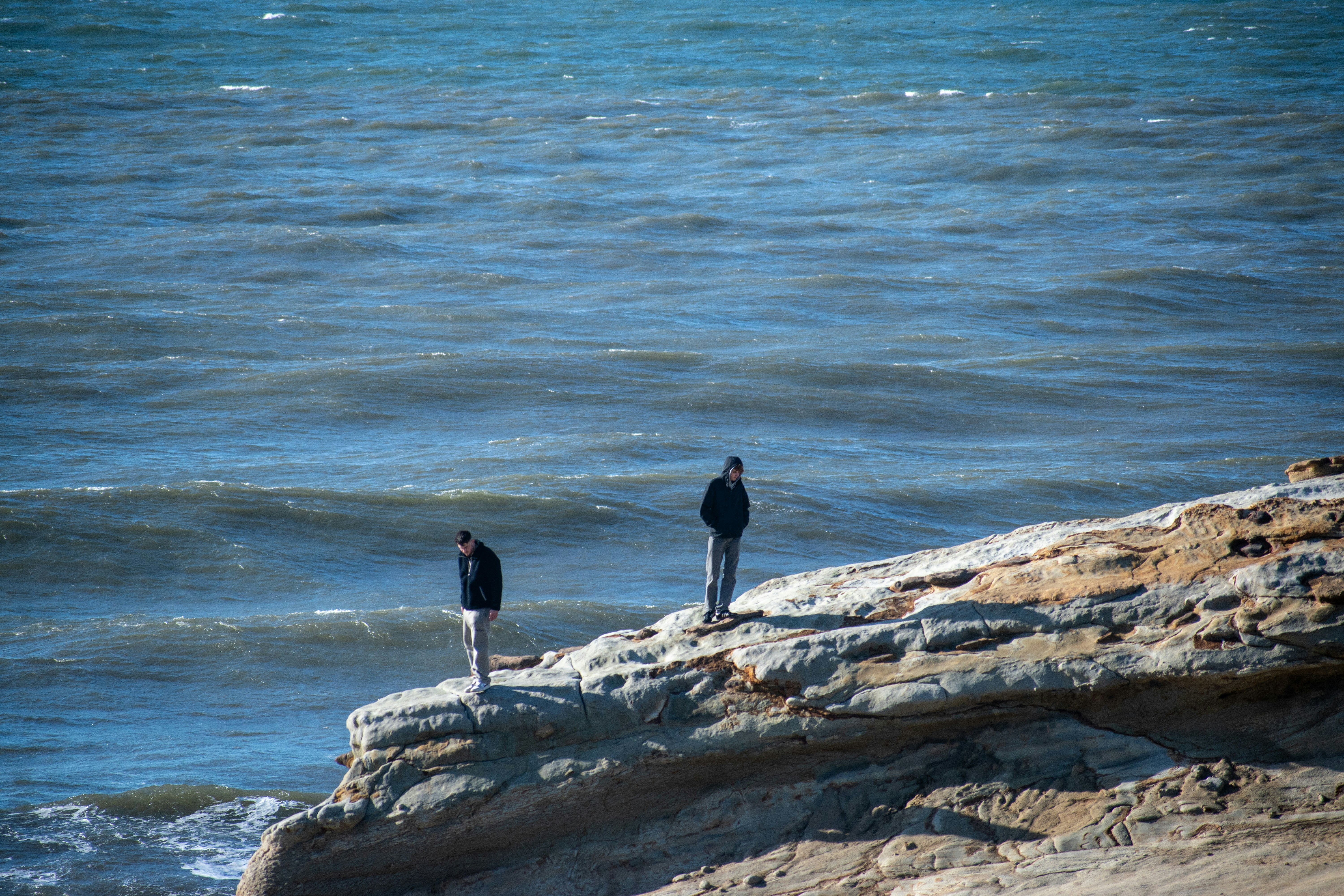 Two Figures Stand Guard on a Wind-Worn Cliff Over the Sea