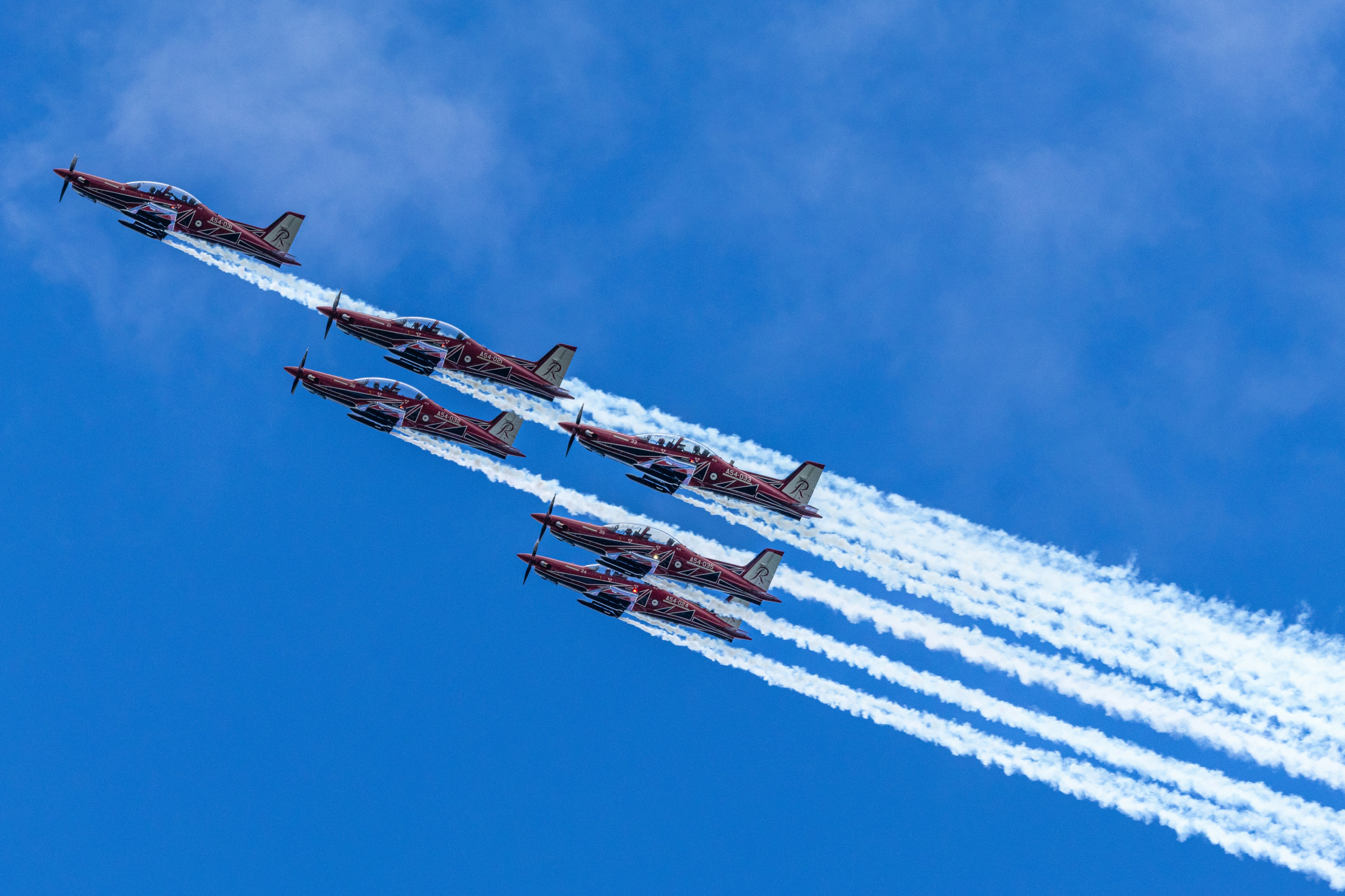 Tandem Diamond: Four Aerobatic Jets Carve Contrails Across a Clear Sky